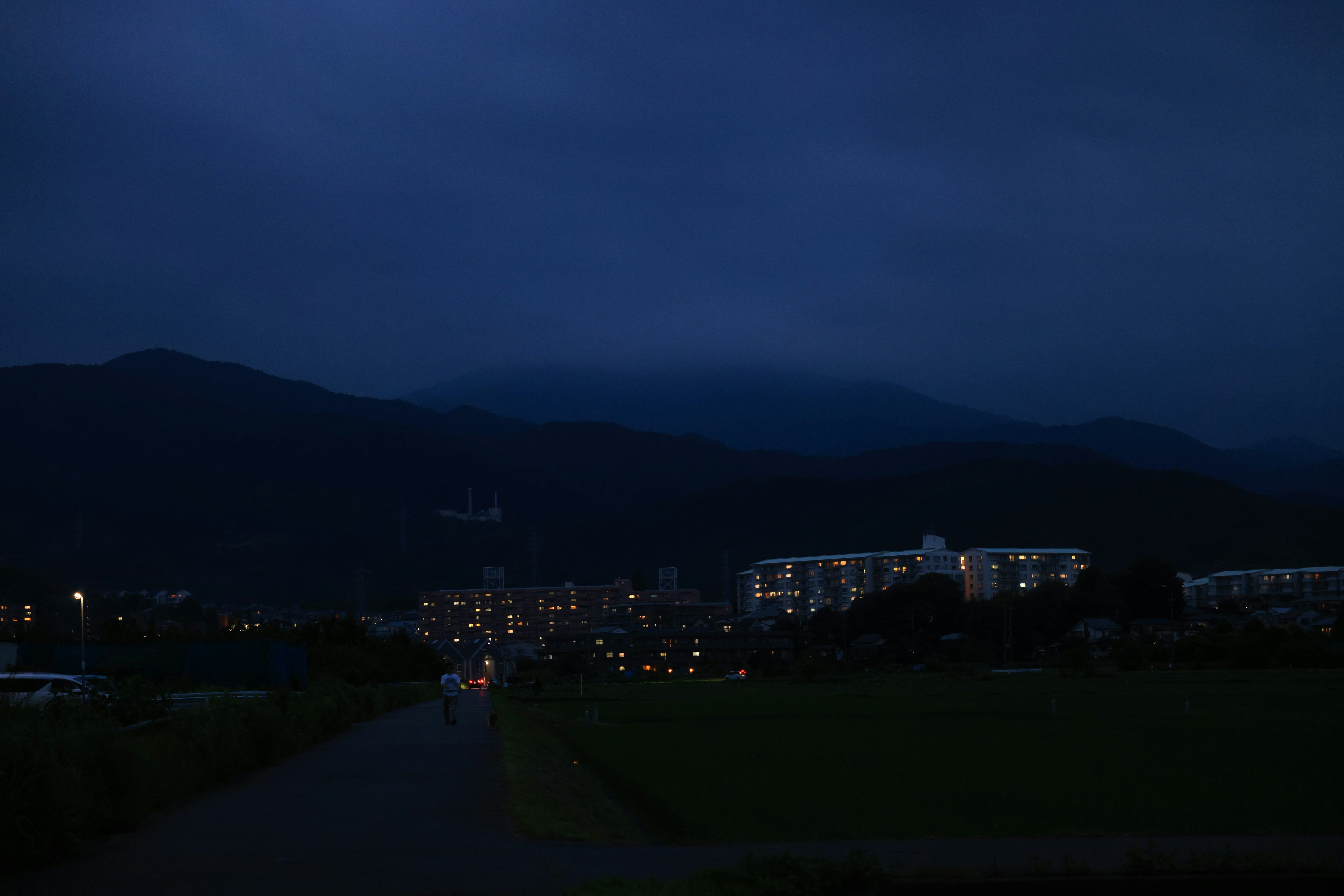 Evening view of a town with lights against dark mountains.
