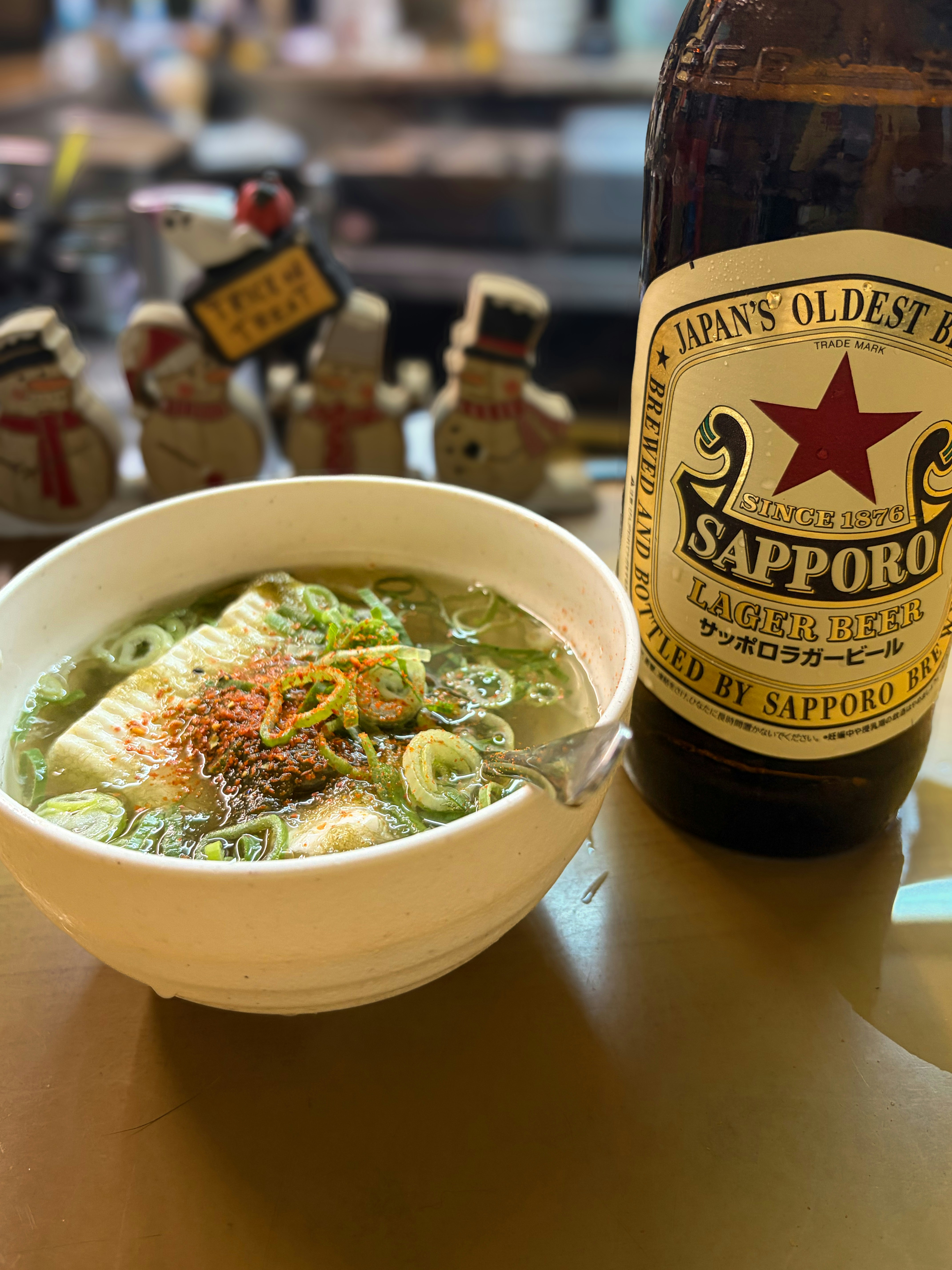Bowl of soup with green onions and a sapporo beer.