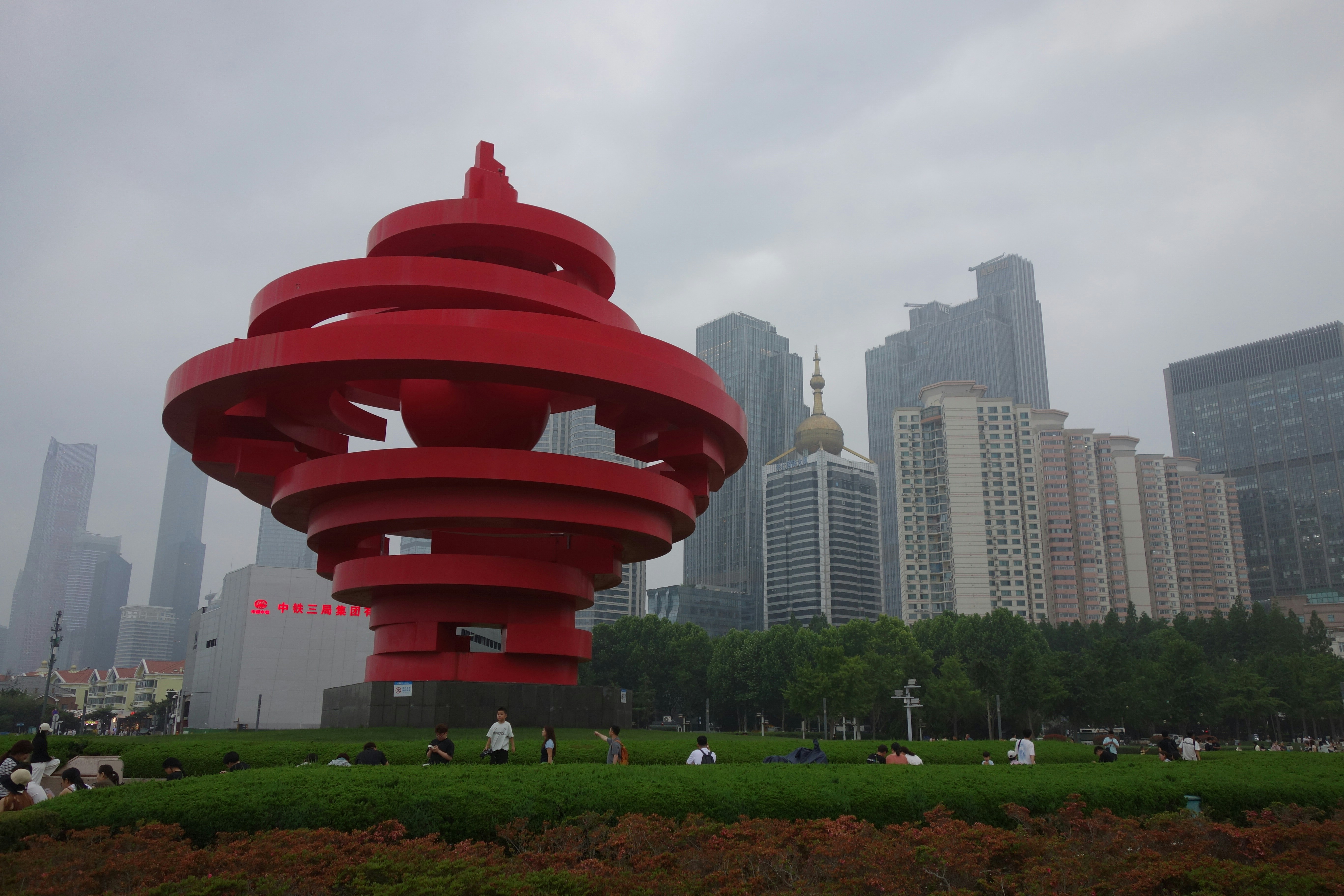Red Spiral Sculpture Reaching Toward the Sky with City Skyline
