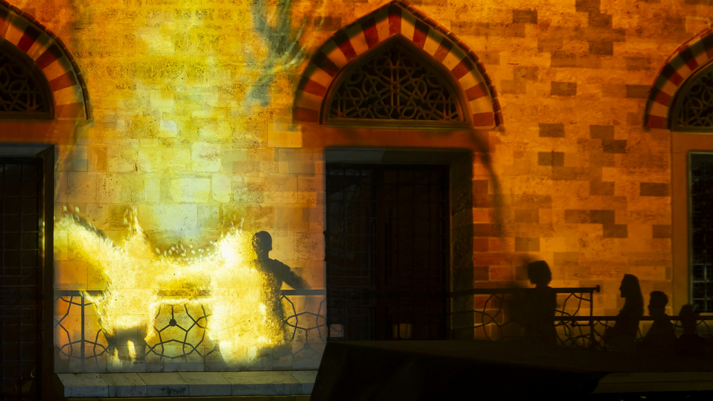 Golden Flames on the Terrace: silhouettes against a historic façade