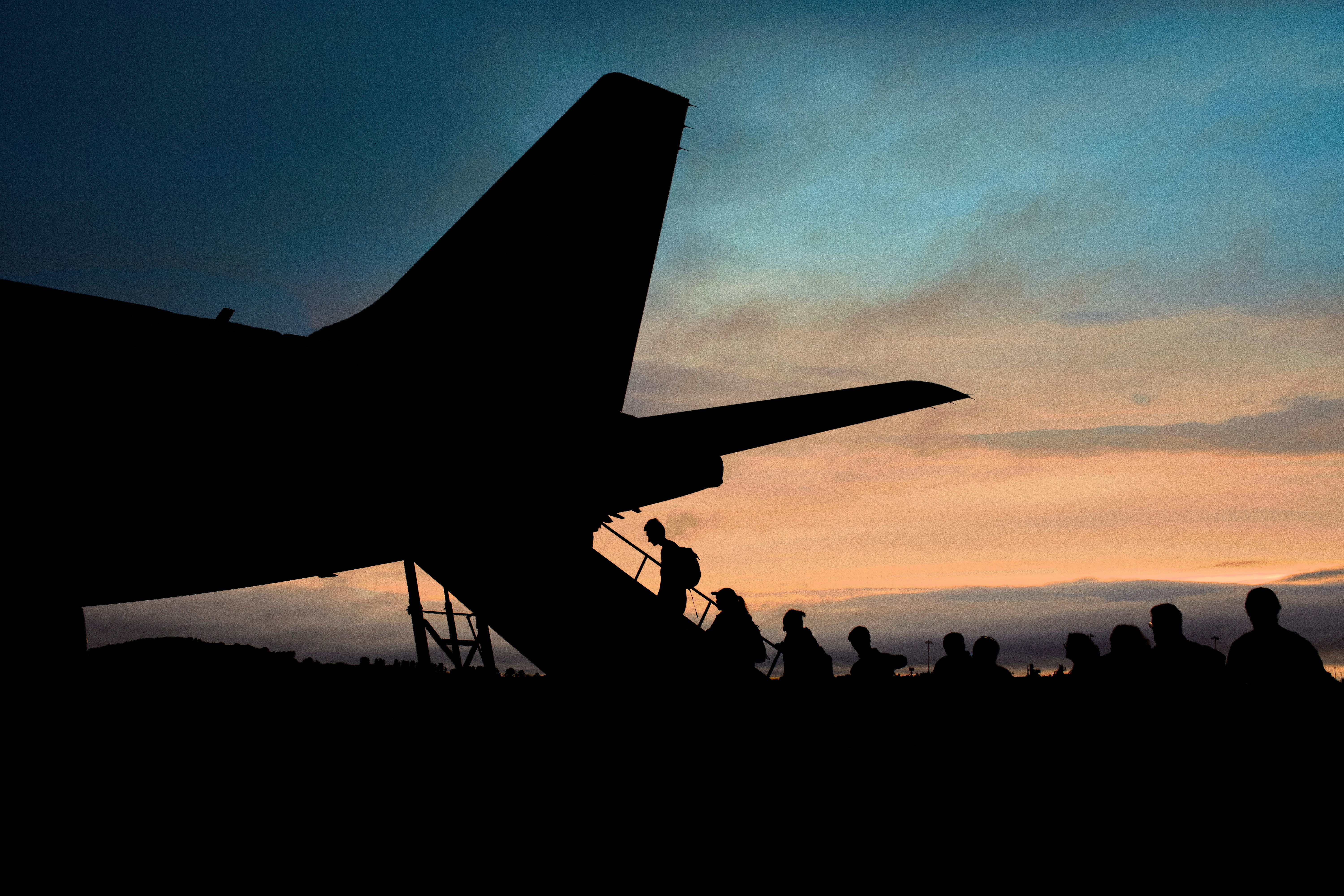 Silhouetted aircrew and aircraft against a twilight runway