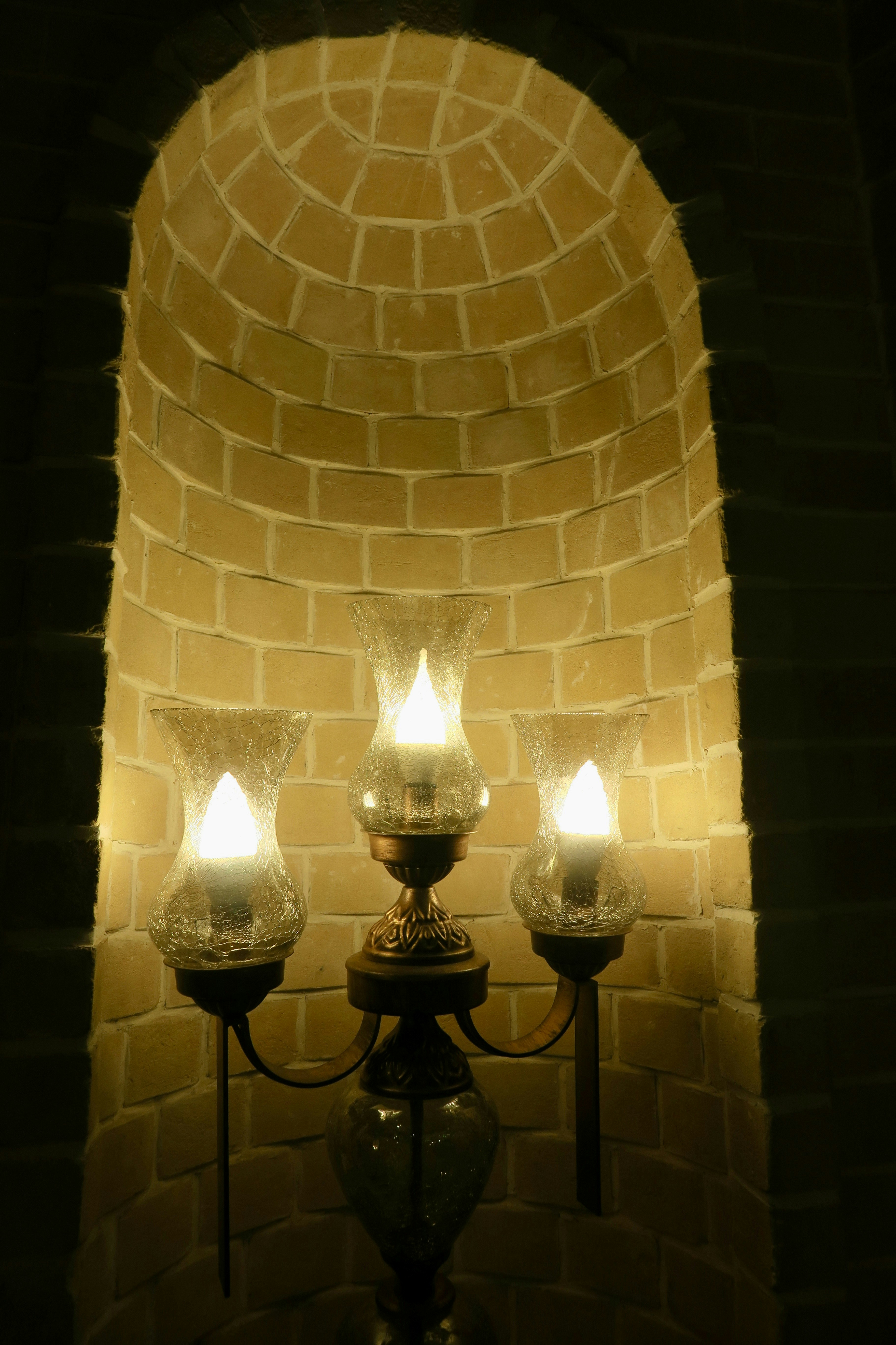 Gas-lit Ambience: A Vintage Candelabras Glow in a Brick Niche