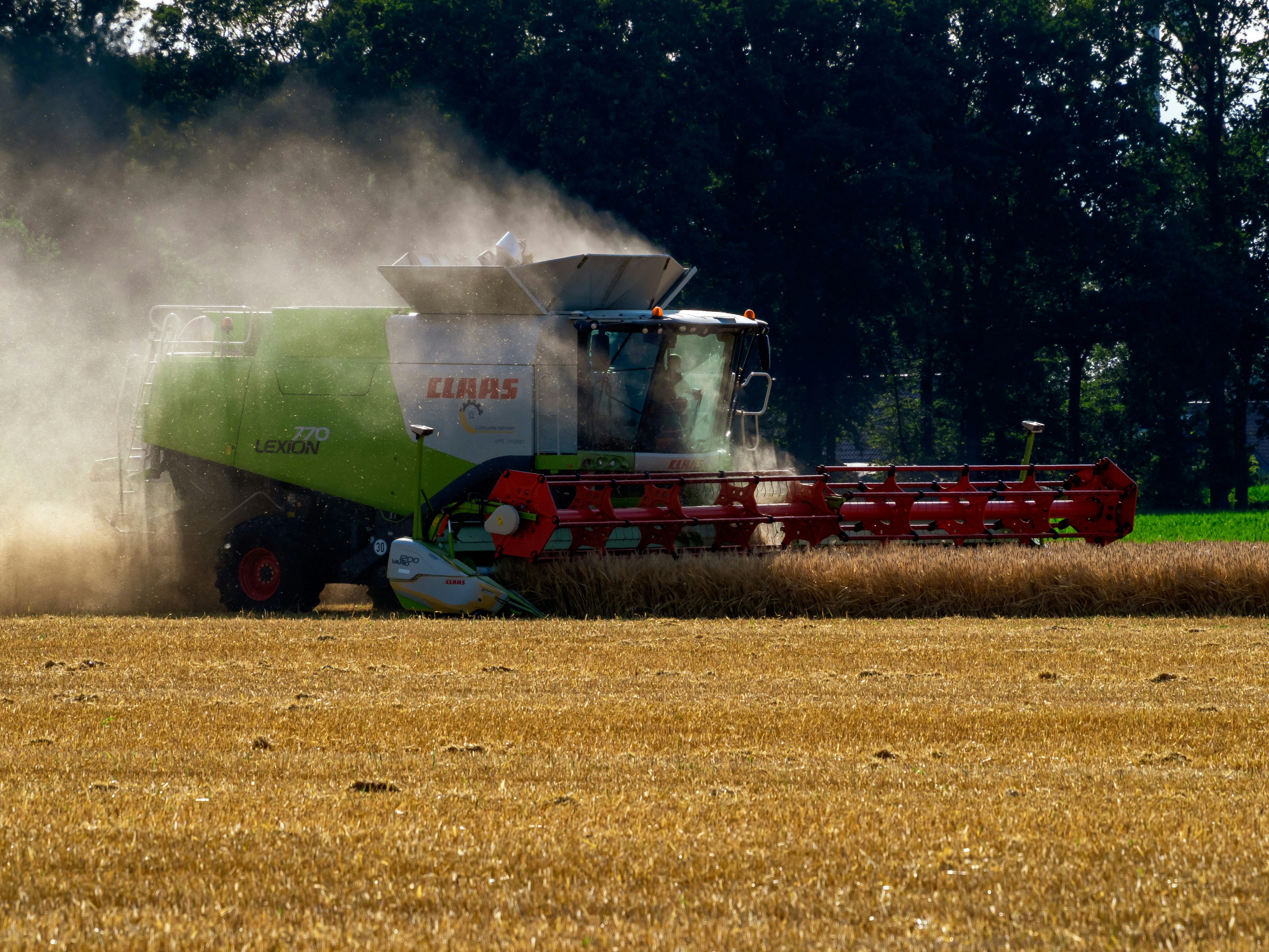 Green Harvesters in Dust: A Field-Streaking Combine at Dusk