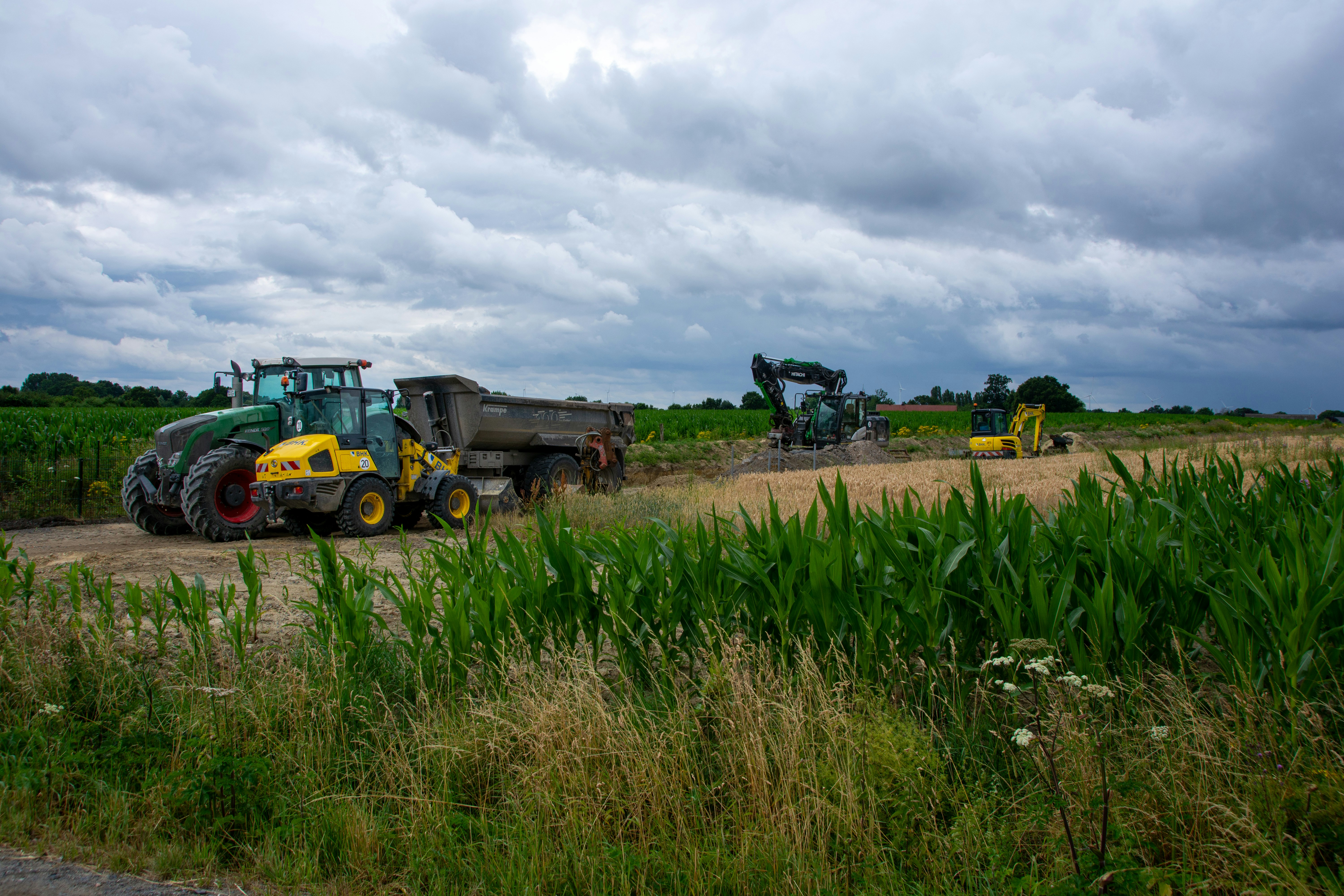 Harvest Machines along a Dusty Field under Brooding Sky