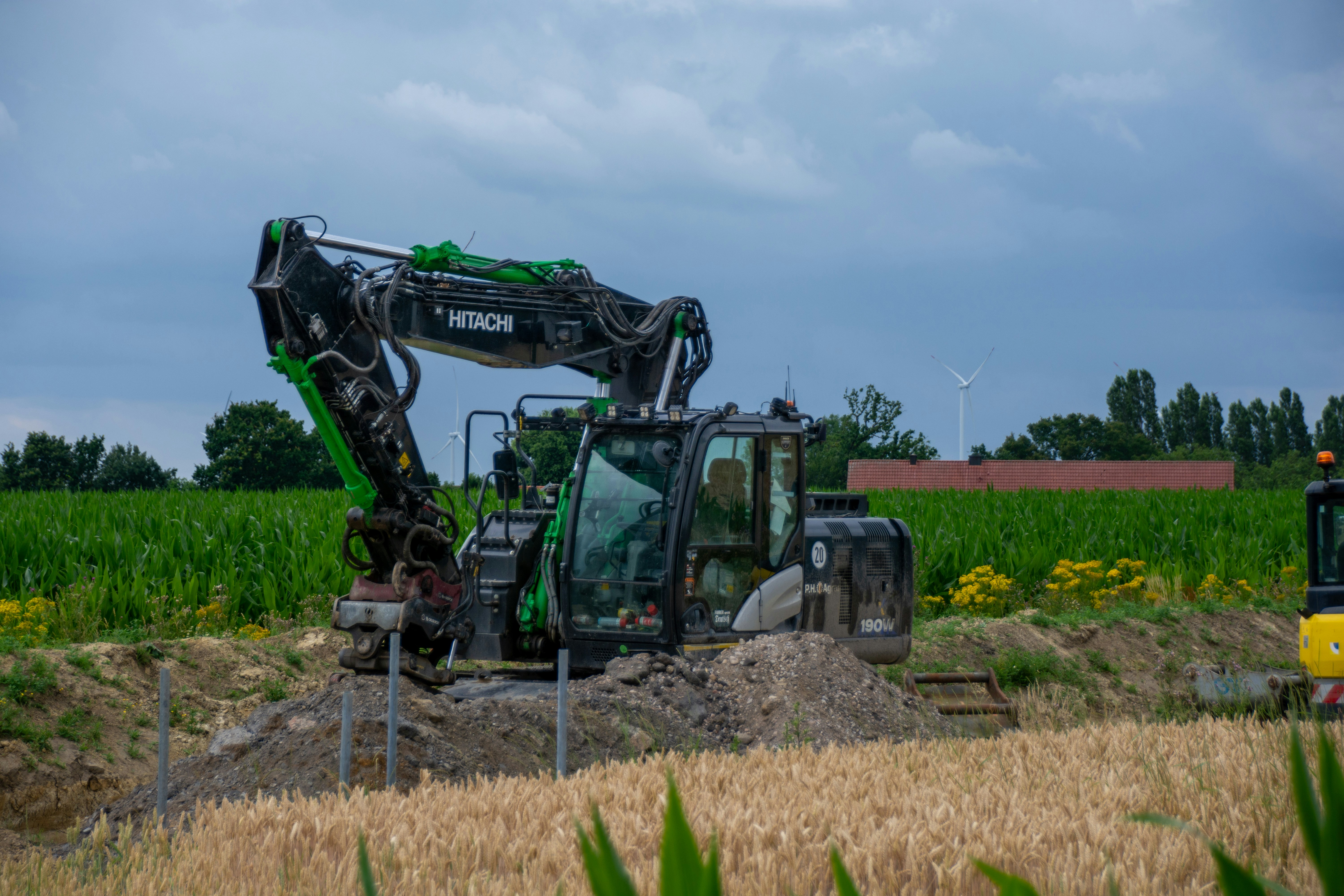 Green Excavator at Work in a Wide Rural Construction Site
