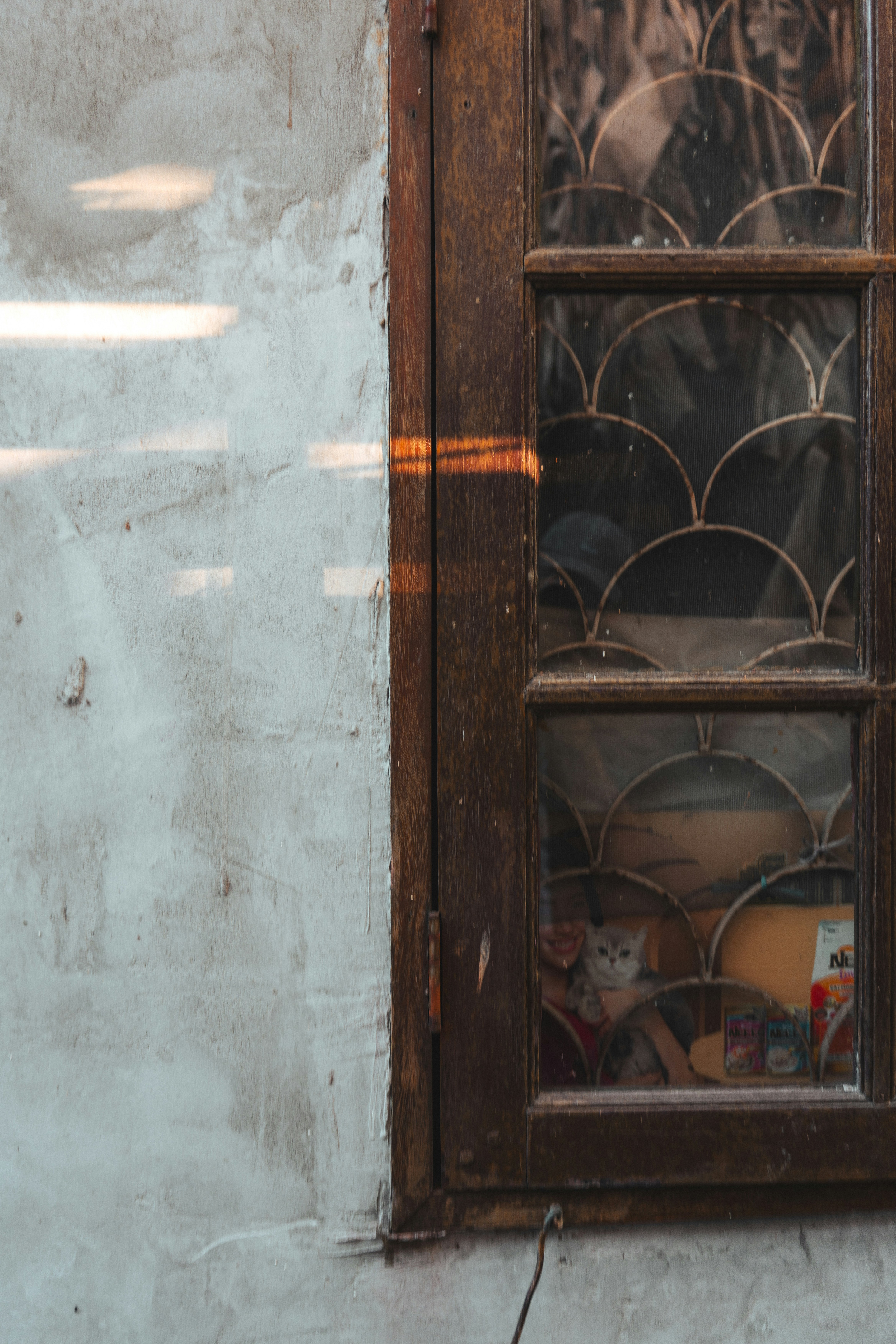 Weathered window, iron lattice and faint reflections in a worn facade