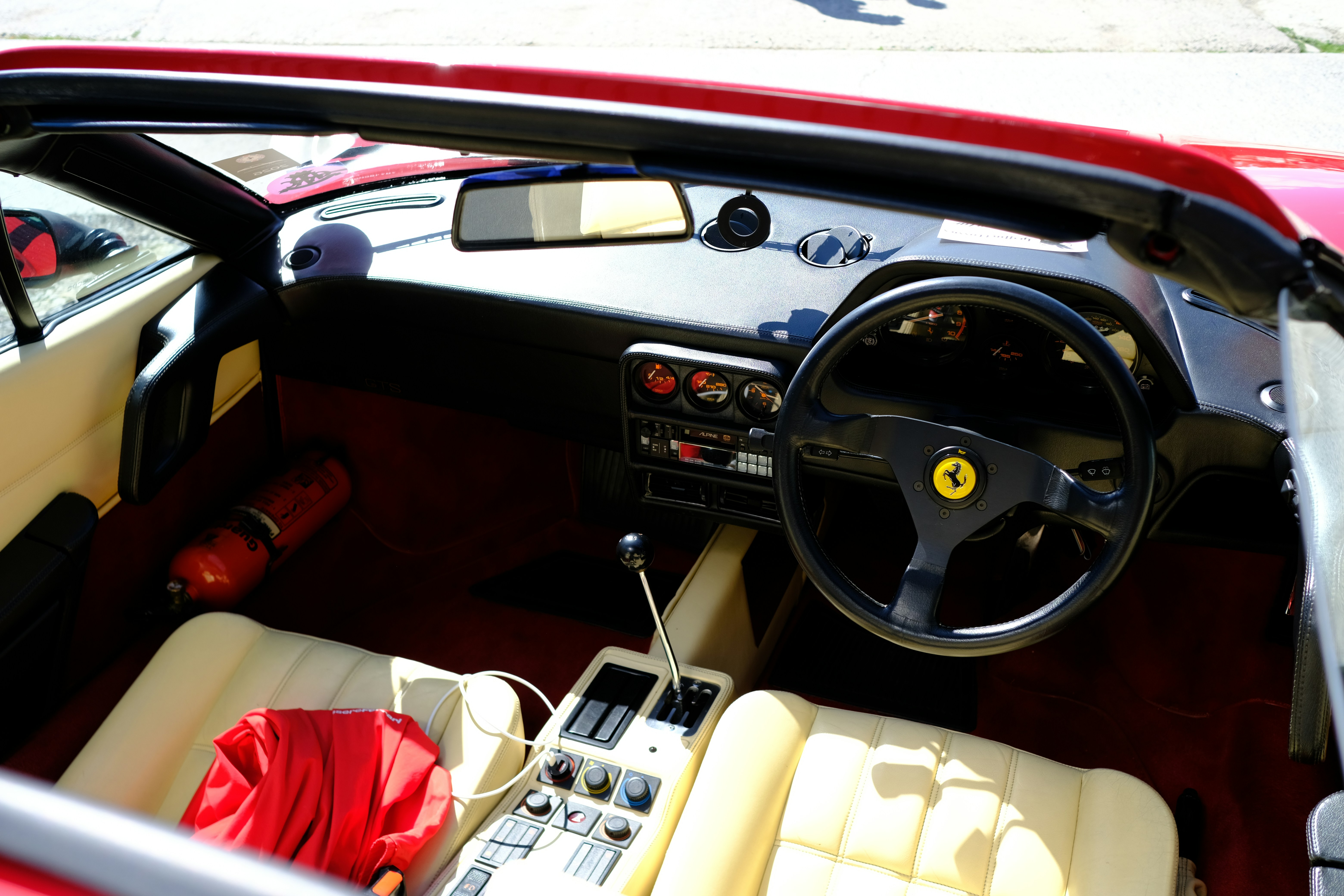 Red ferrari interior with cream seats and black dashboard.