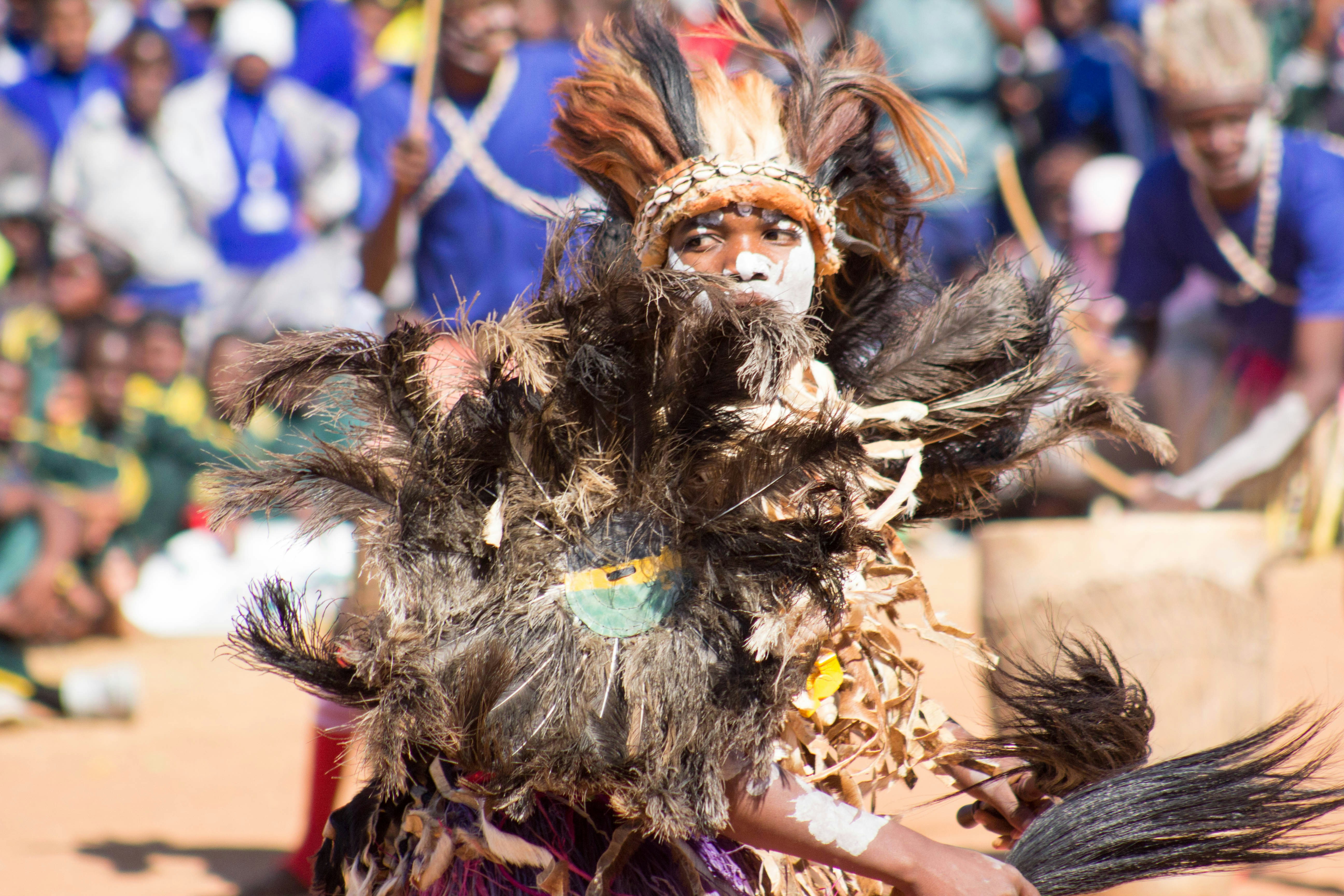 Masked Dancer in Feathery Armor at a Colorful Festival