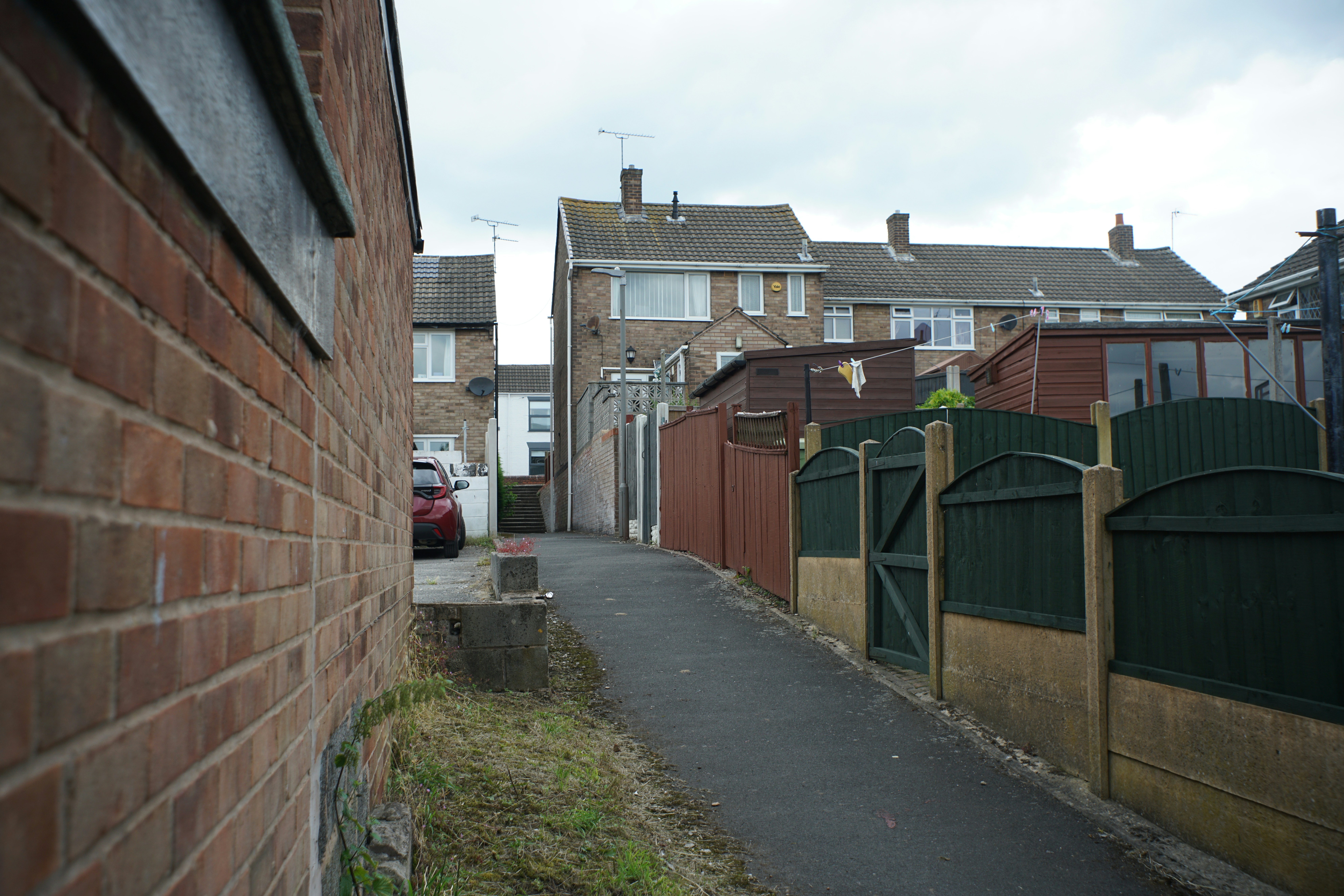 Narrow Alleyway Between Brick Facades Leads to Quiet Street