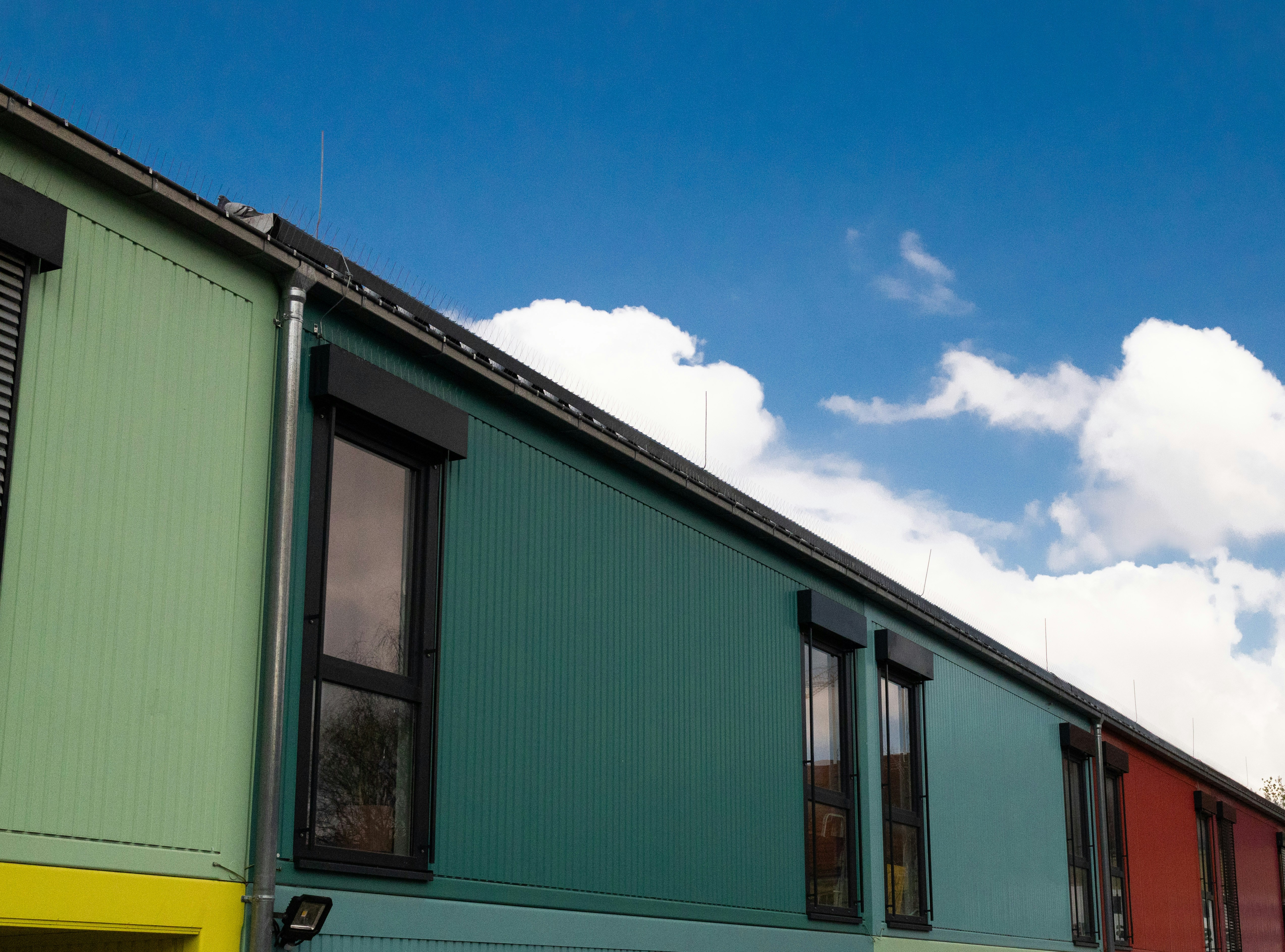 Vibrant multi-hued brick building under a clear blue sky; bold vertical panels create graphic color blocks and sharp window lines.