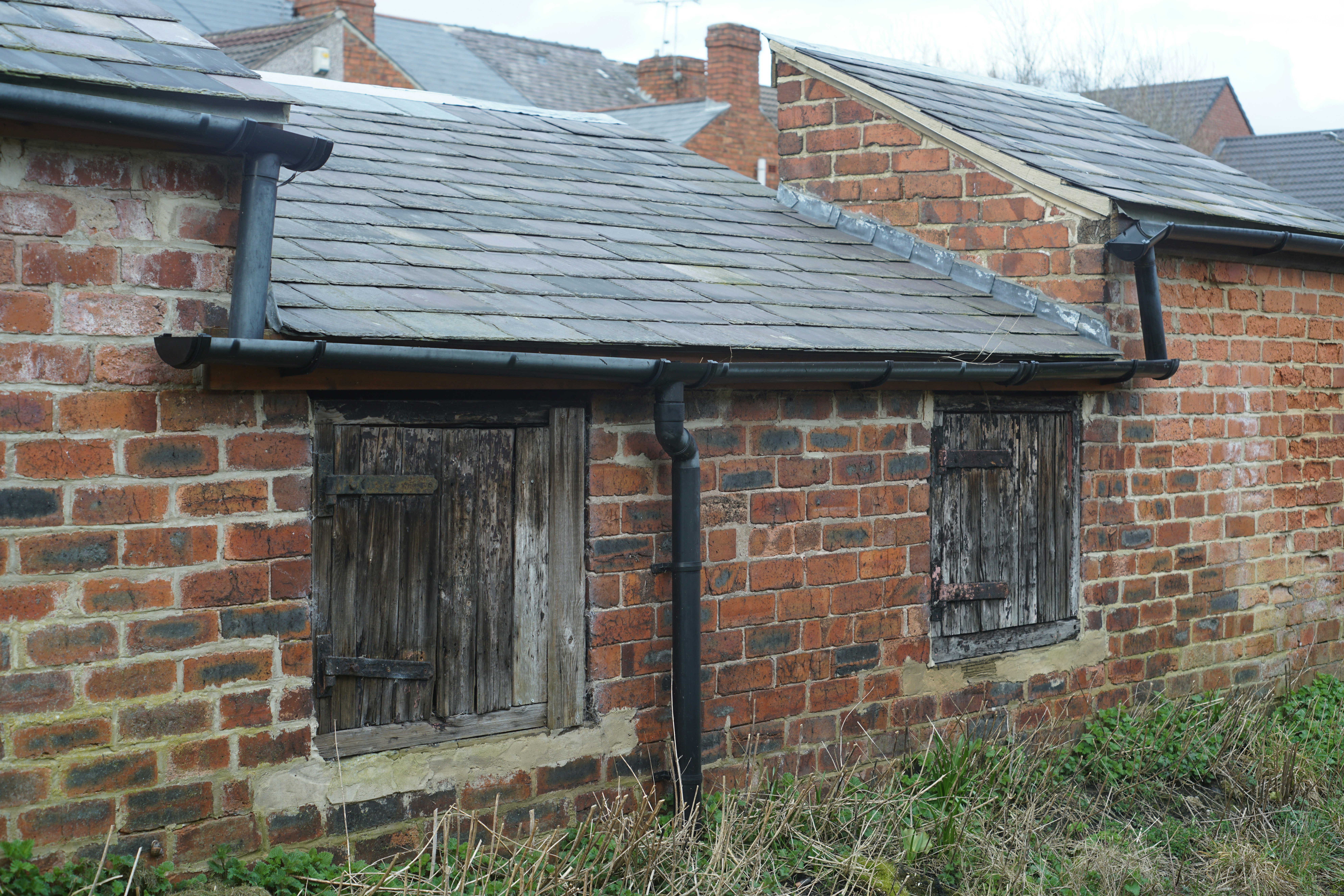 Weathered Brick Outbuildings with Shuttered Doors by a Brick Wall