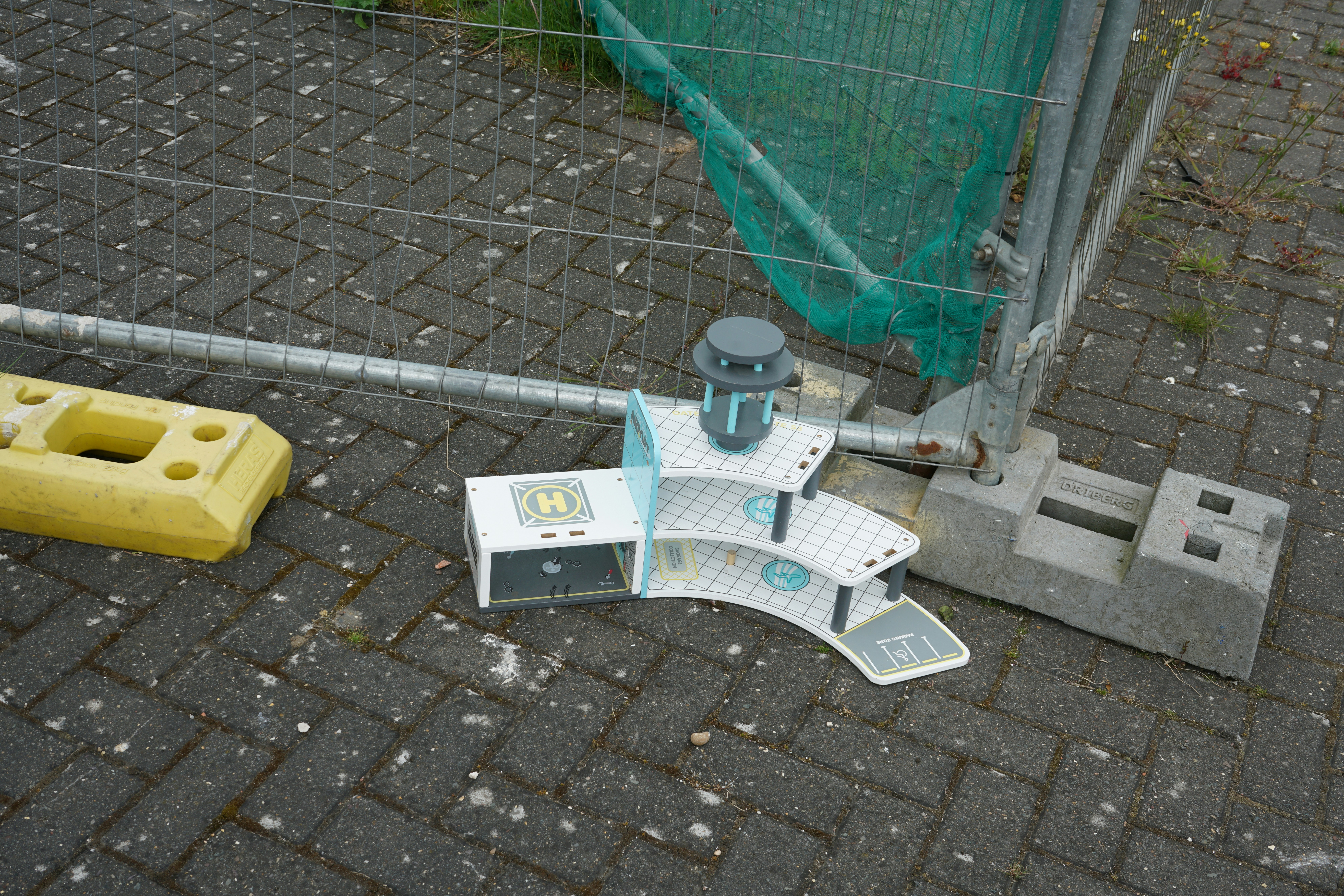 Broken toy project on a construction site under a green mesh fence
