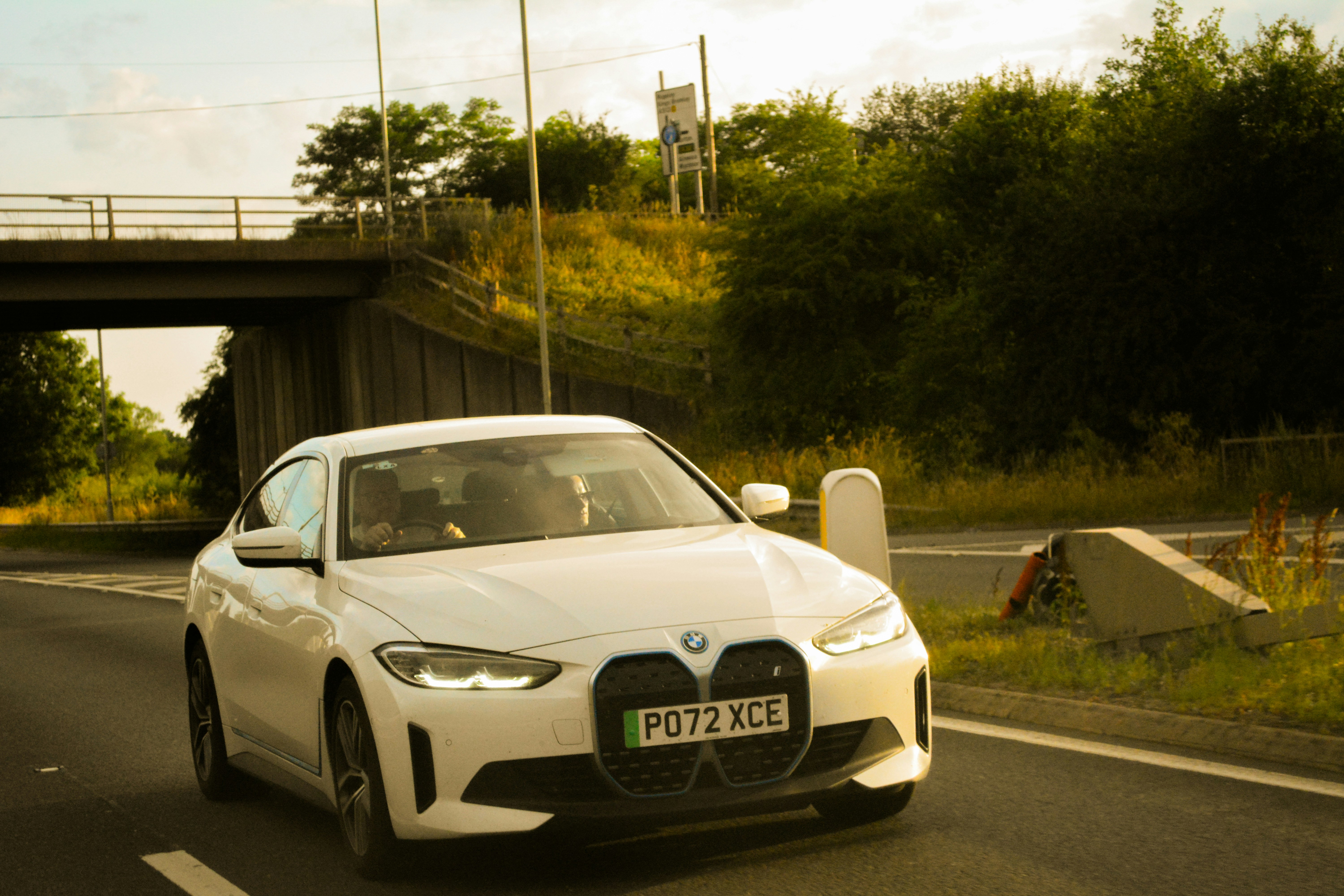 White BMW Emerges on a Suburban Road at Dusk