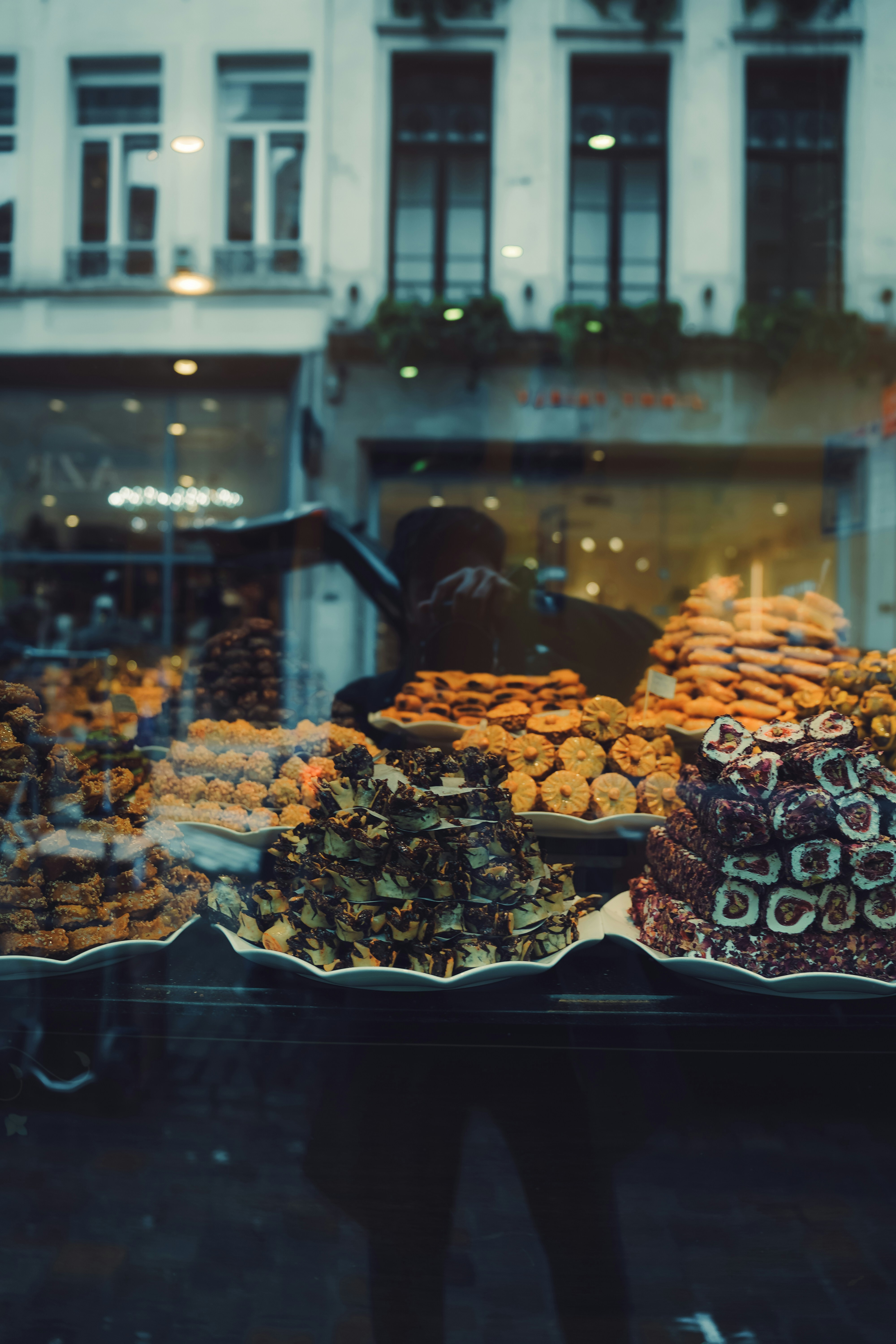 Street Treats Through Glass: A Bakery Display in Soft Evening Light