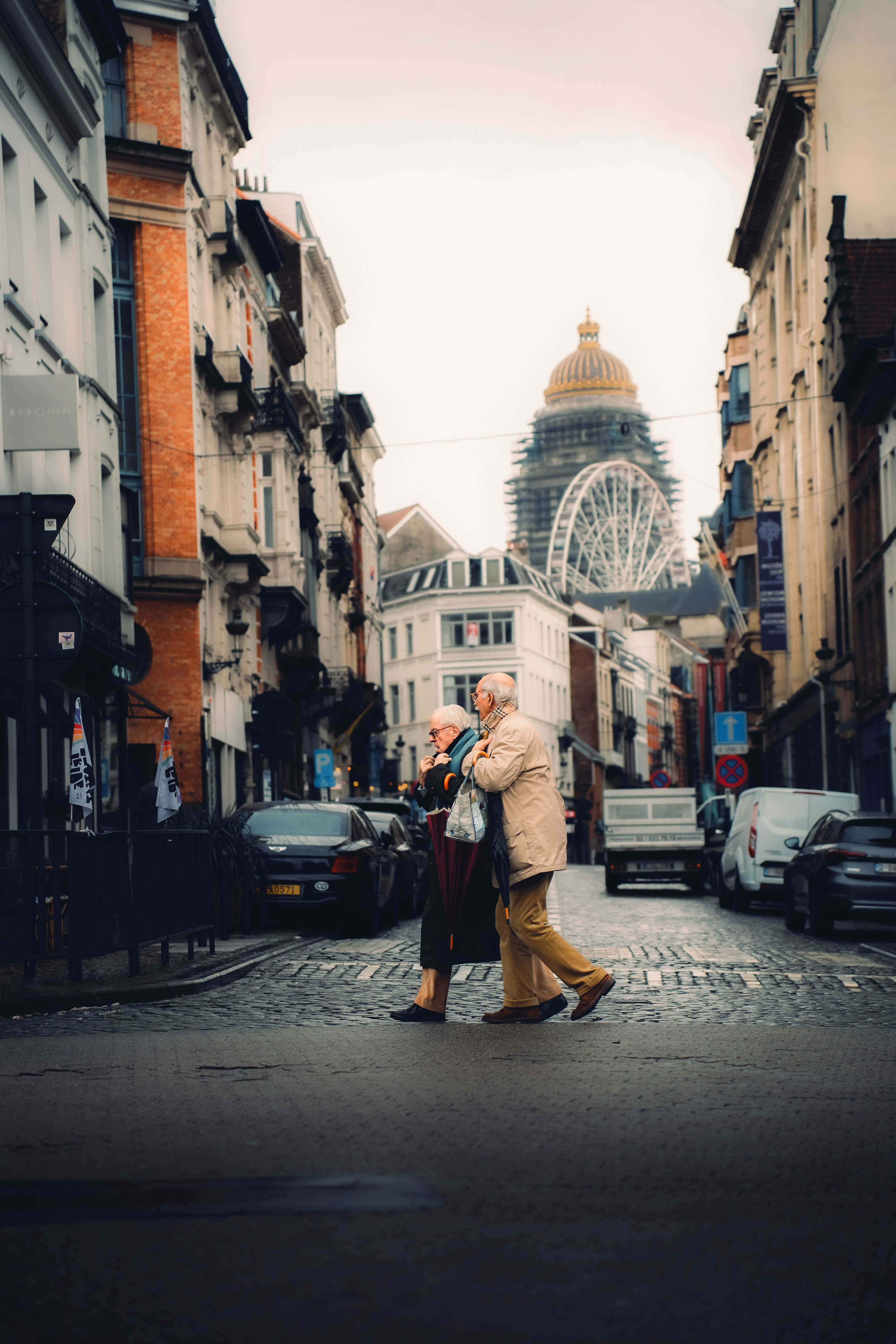 Older couple strolling across a european city street.