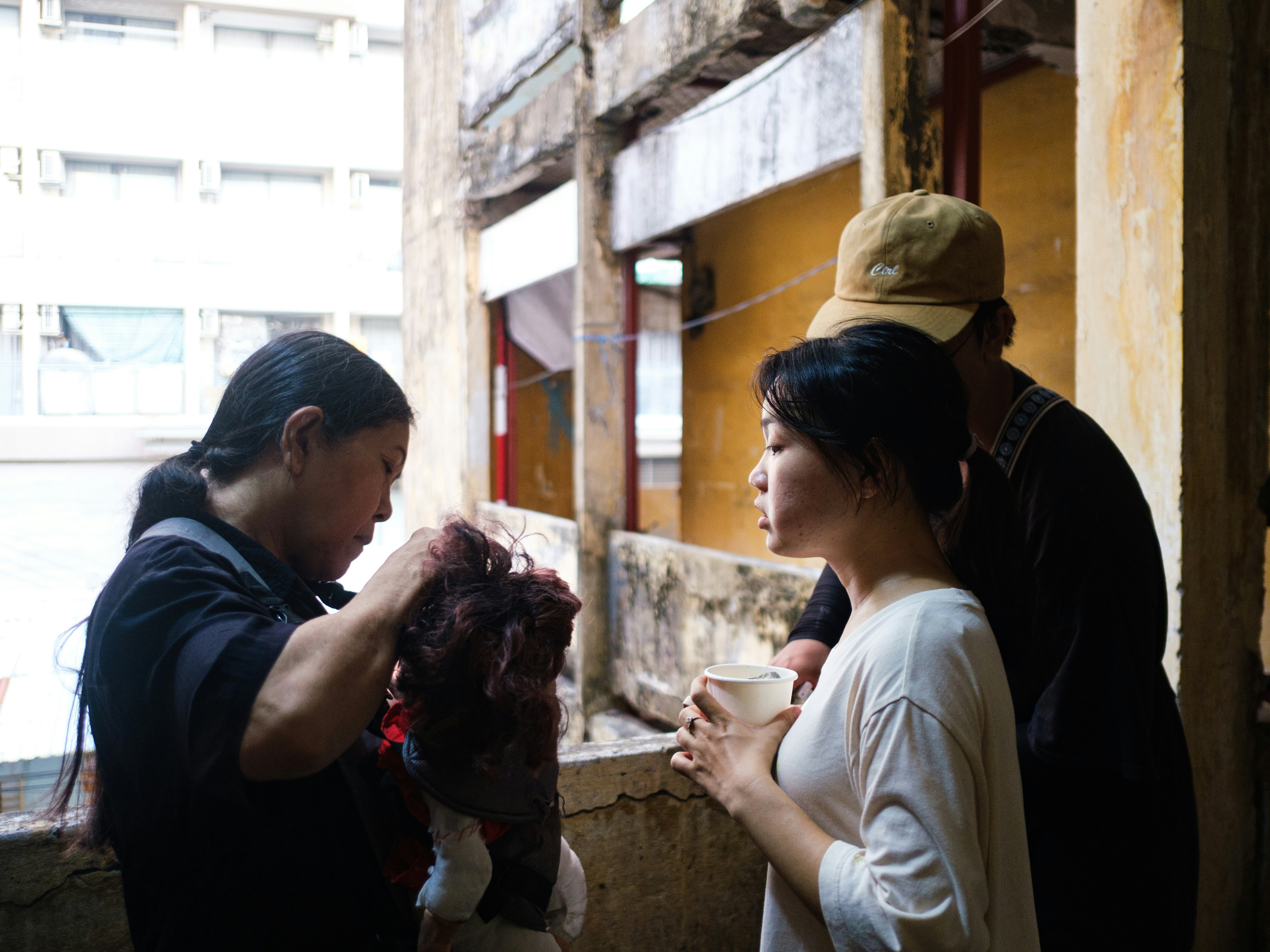 Three people interact in a rustic indoor setting