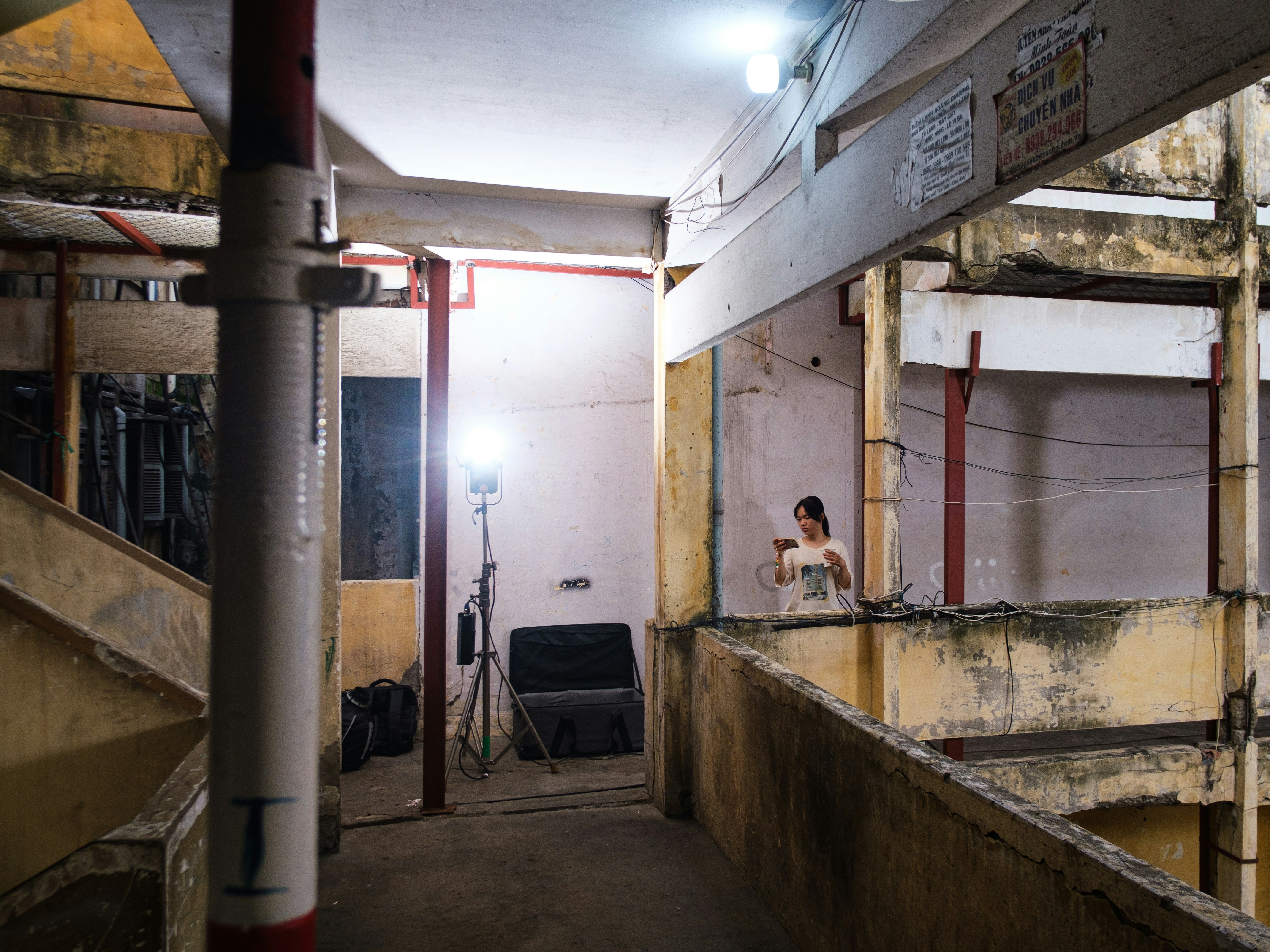 Bandaged Light: A lone figure in an industrial stairwell under stark fluorescent glare