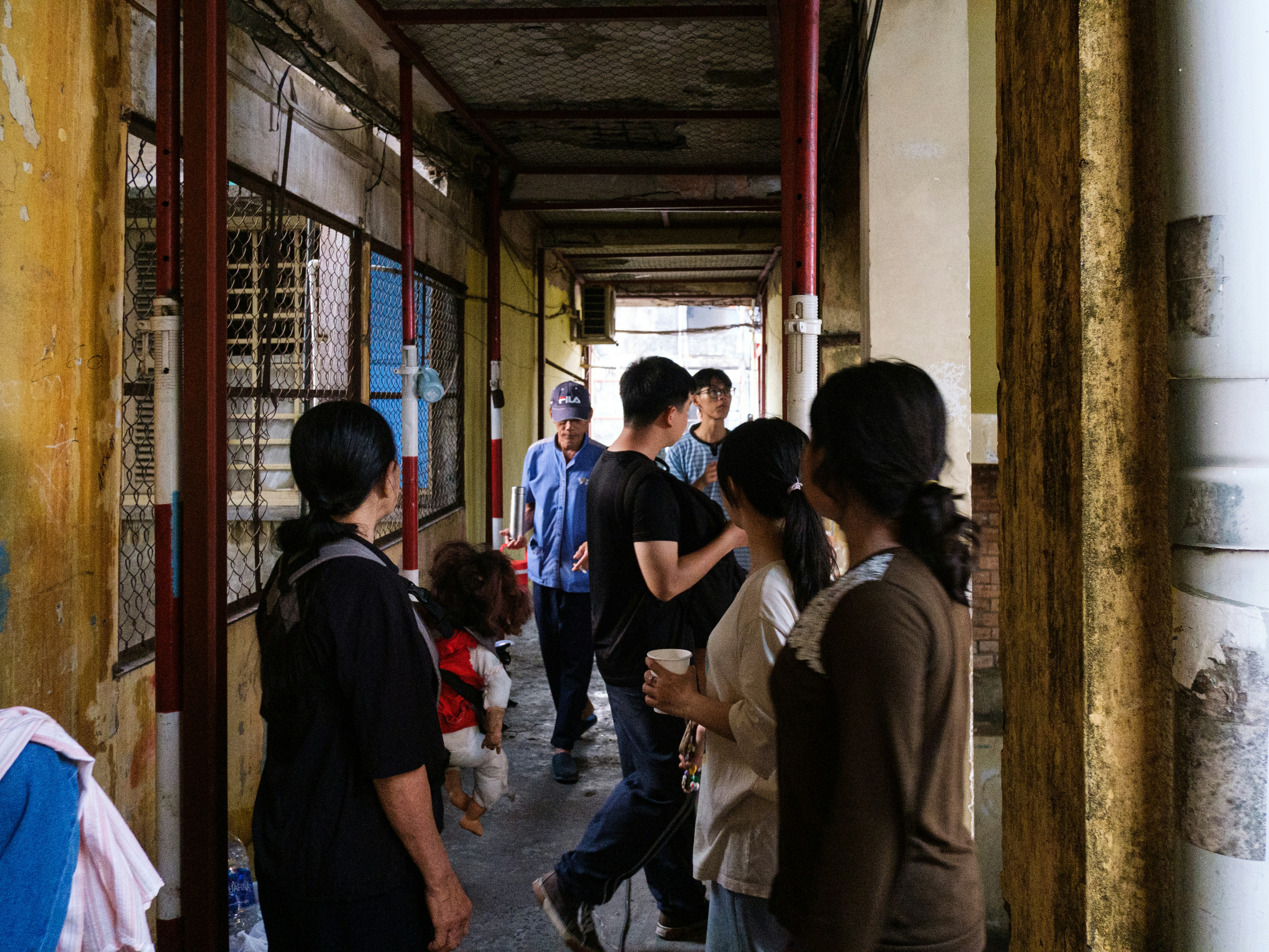 Quiet Corridor Convergence: People Gather in a Weathered Passage