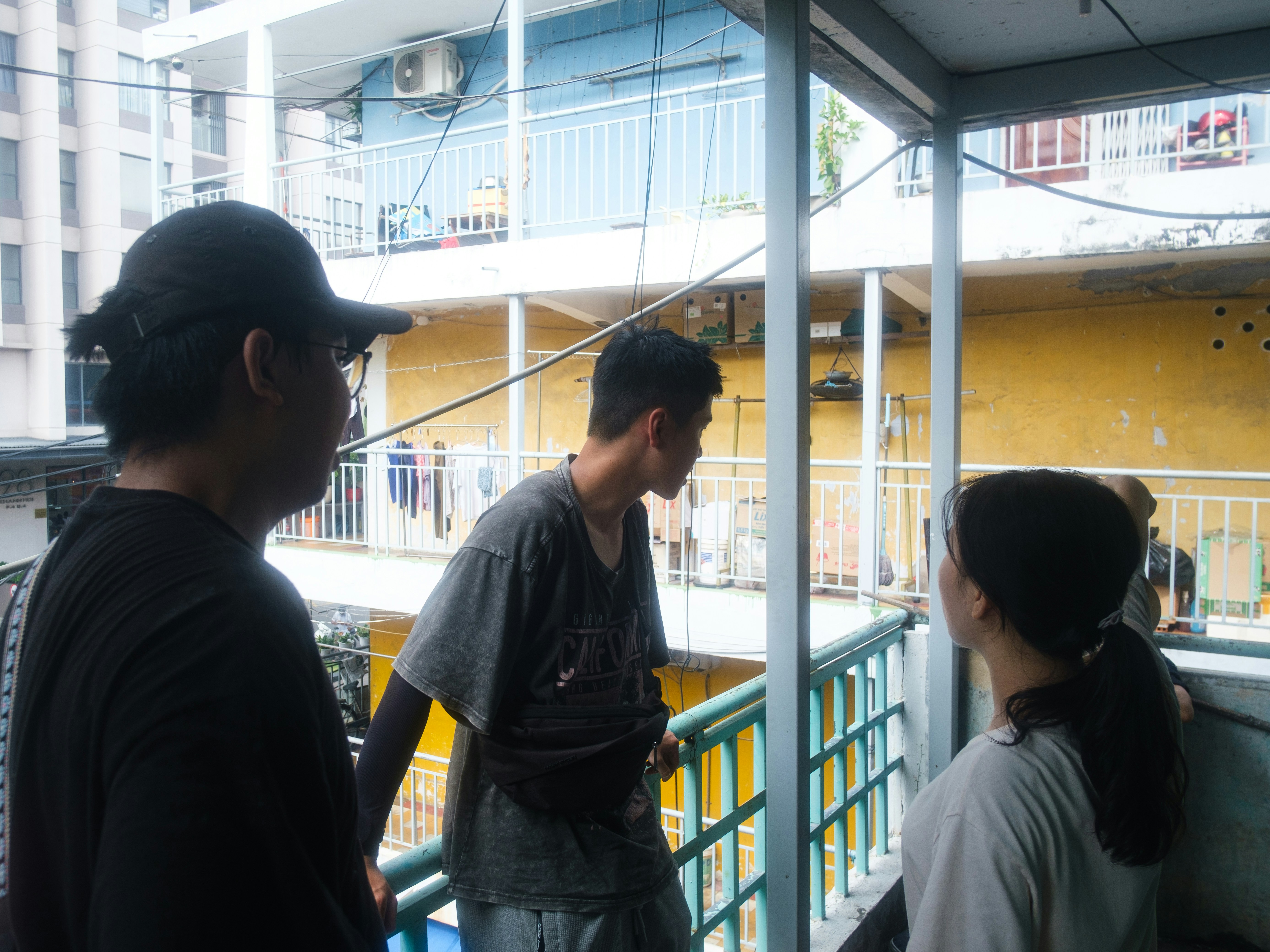 Three Observers on a Balcony: Conversation beneath a City Scaffold