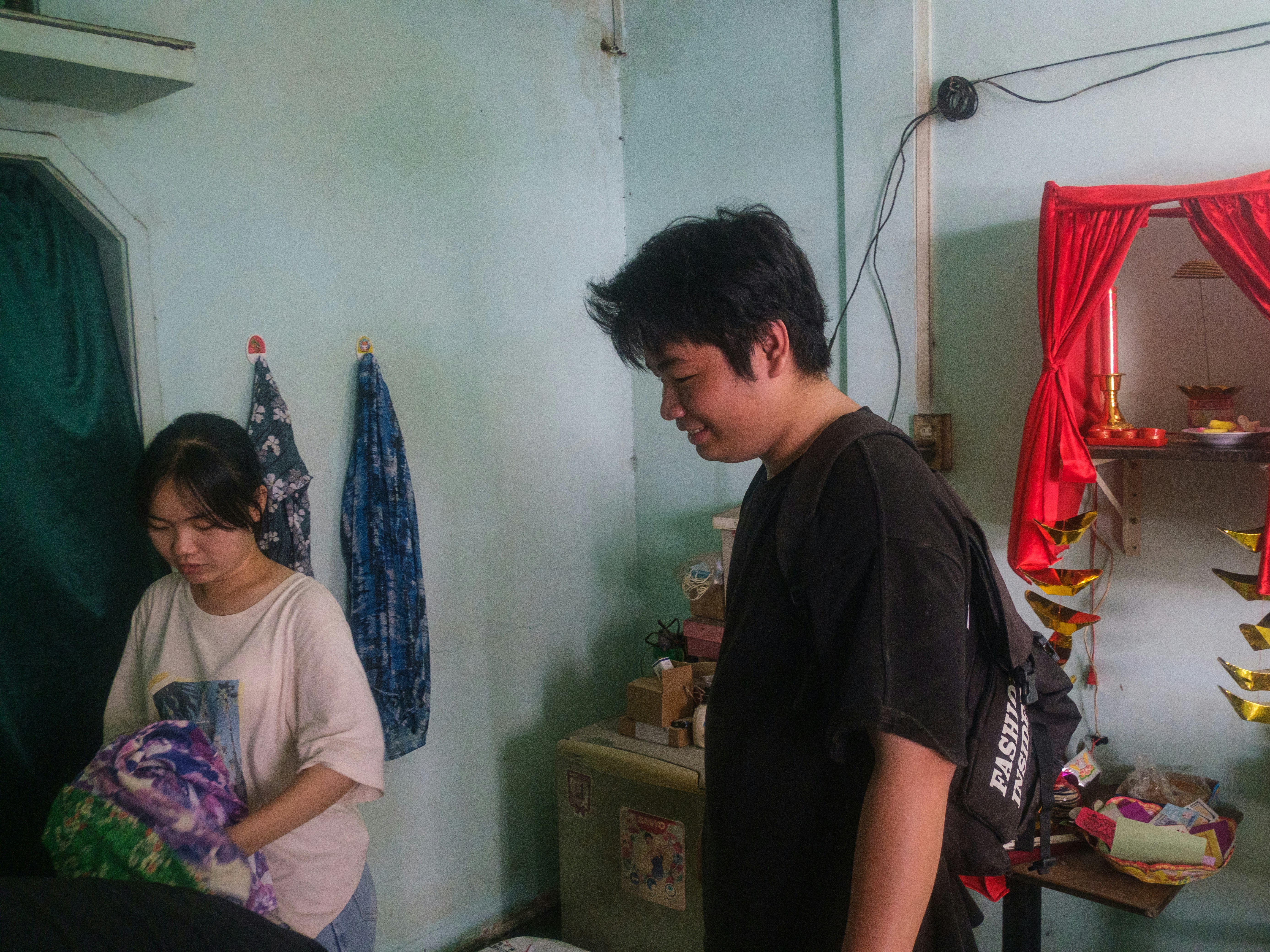 Quiet Moment in a Shrine Room: Two Visitors by a Backlit Altar