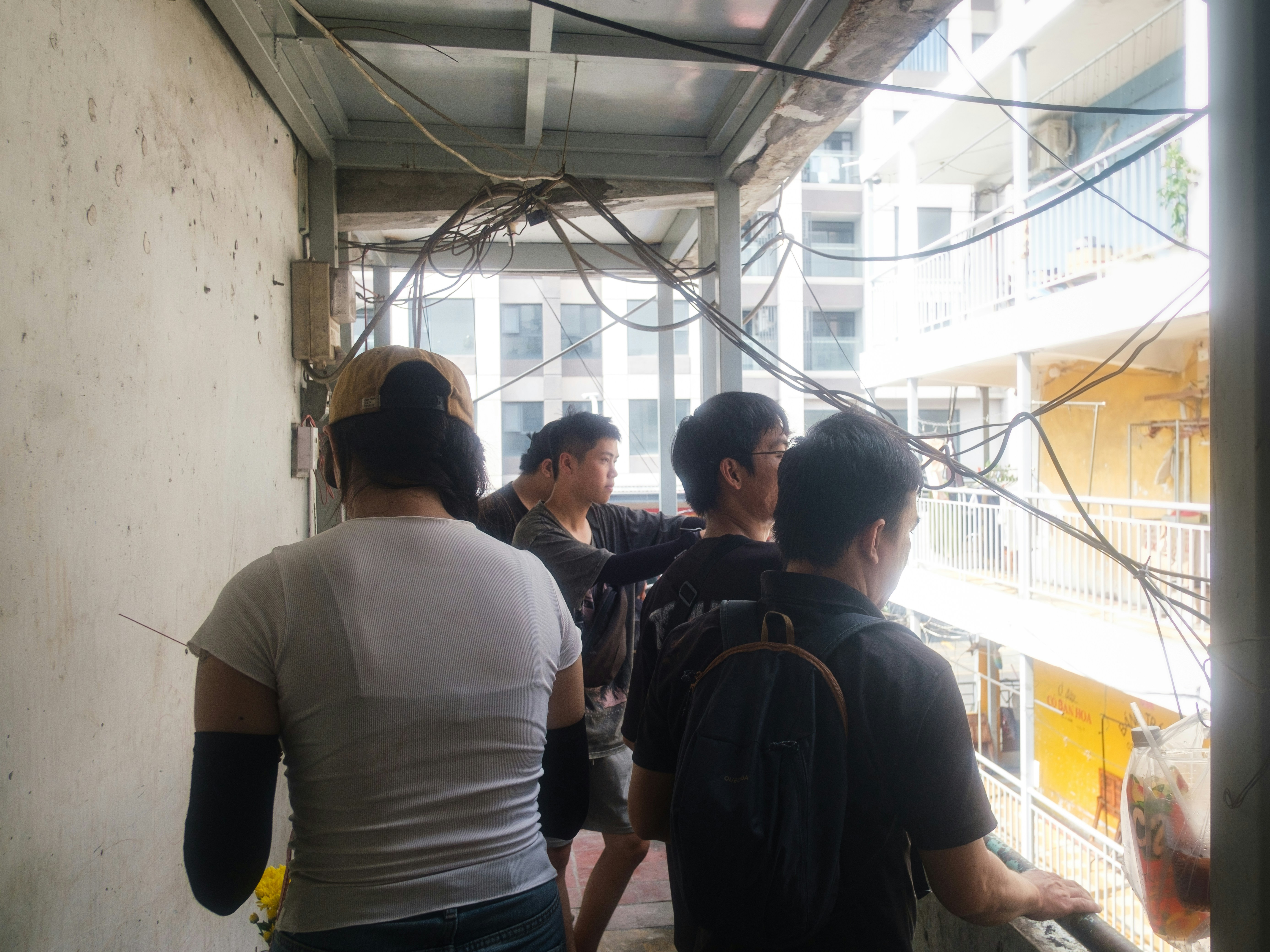 Crew of Urban Explorers Huddle Amid Exposed Wires in a Sunlit Atrium