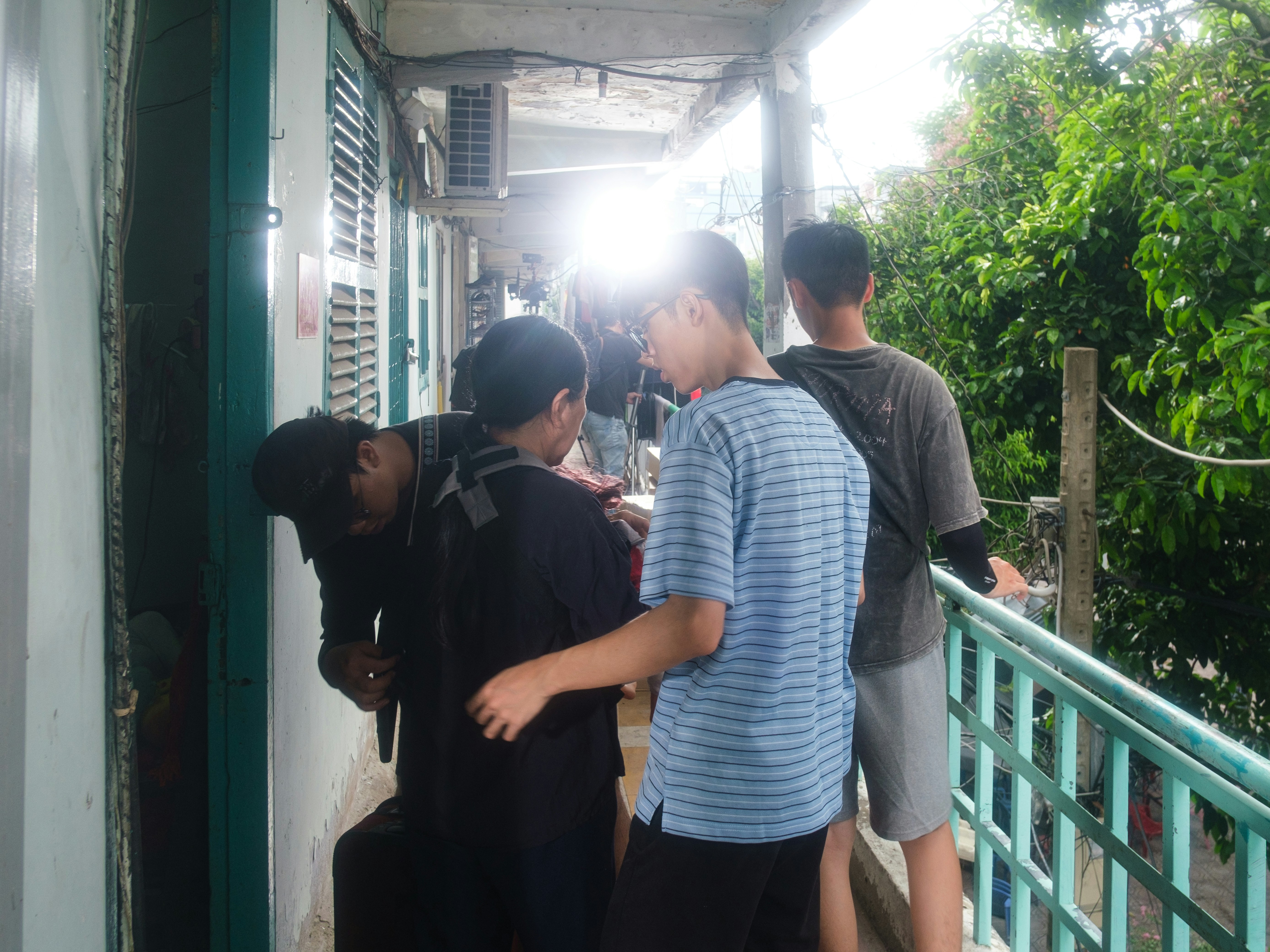 Over-Shoulder Portrait Corridor: People Gather in a Sunlit Balcony