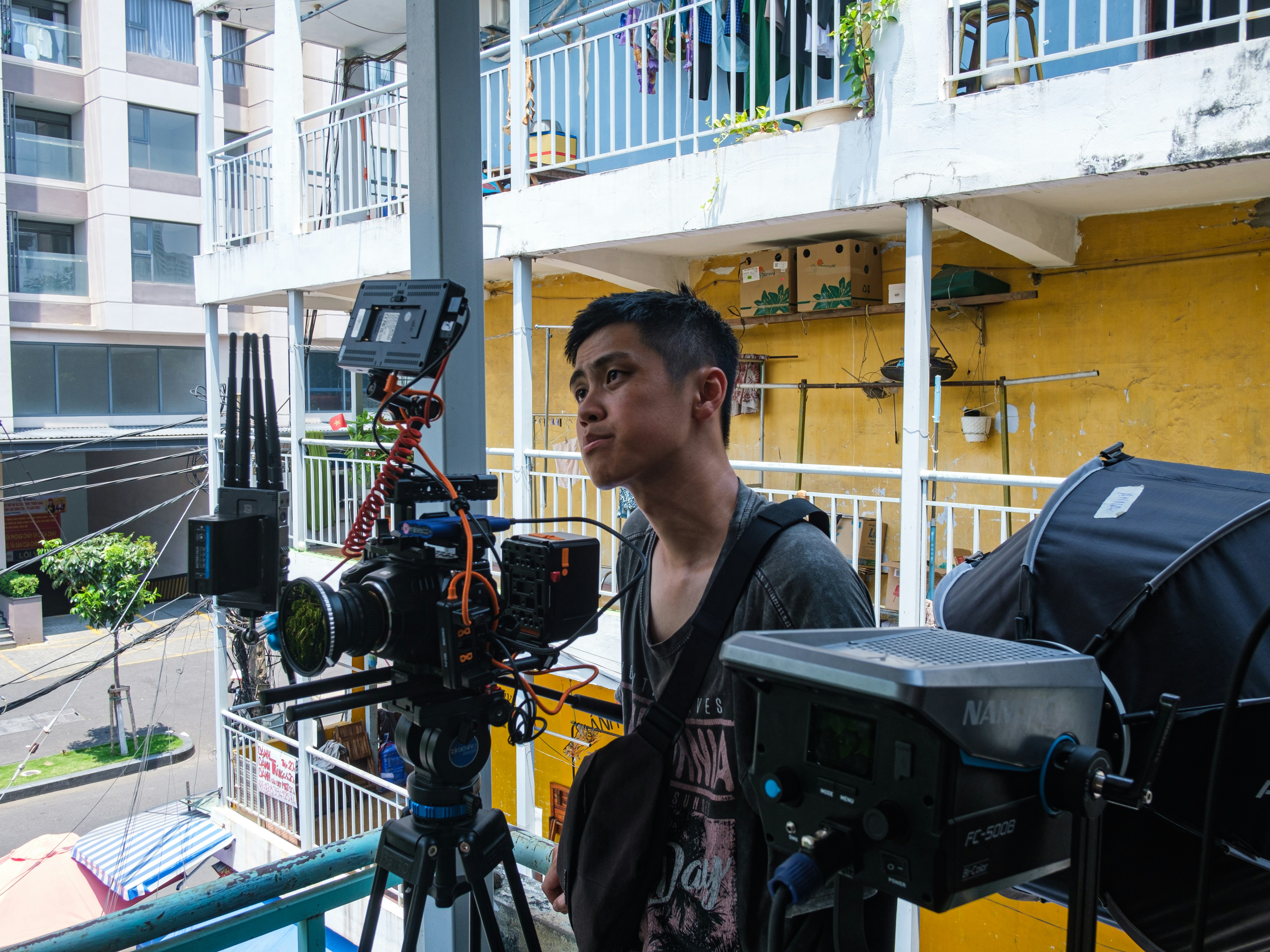 Portrait of a filmmaker behind the camera rig on a sunlit rooftop
