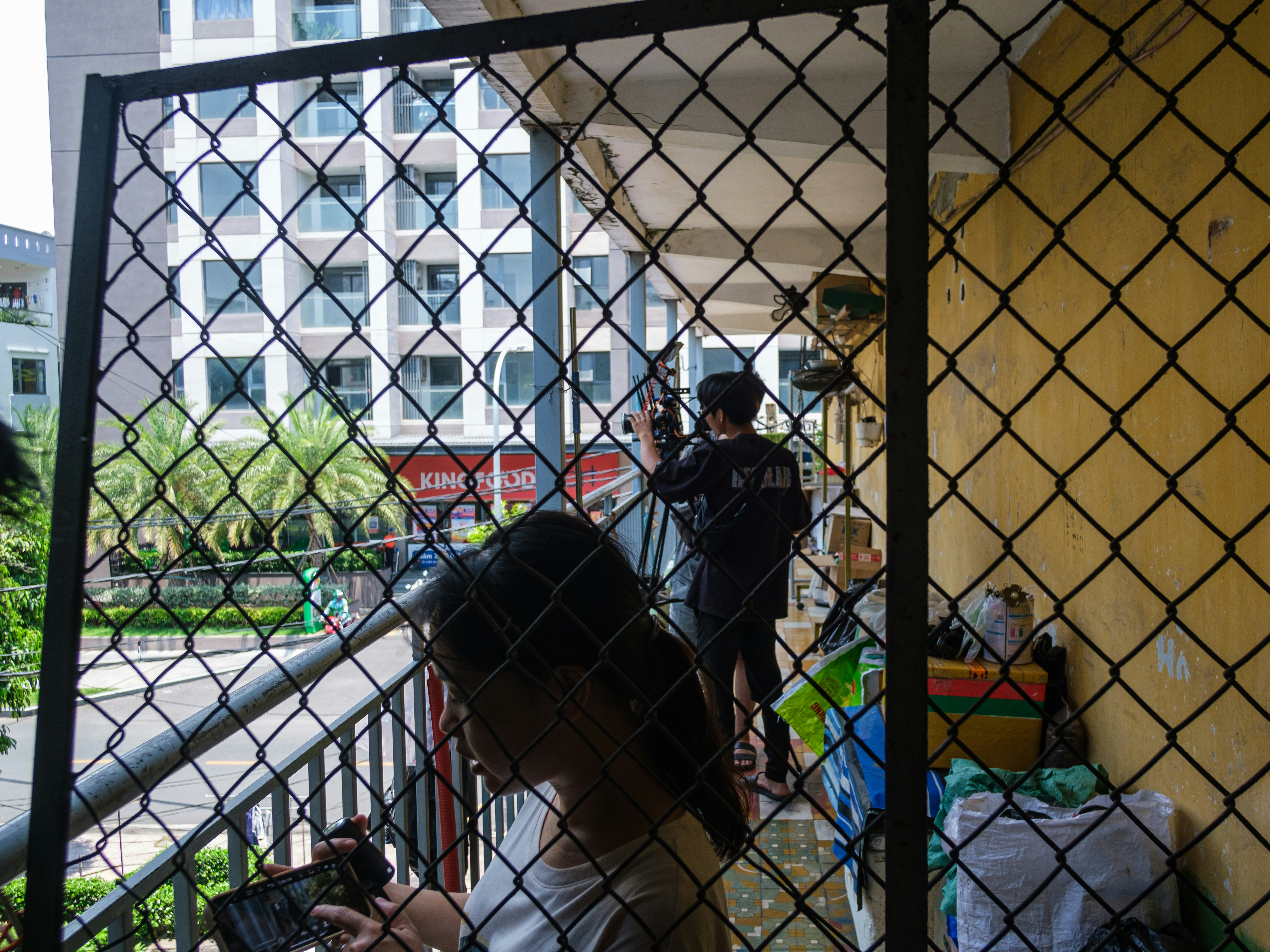 Balcony Portrait: A Photographer Captures the City Vivo Through a Chain-Link Frame