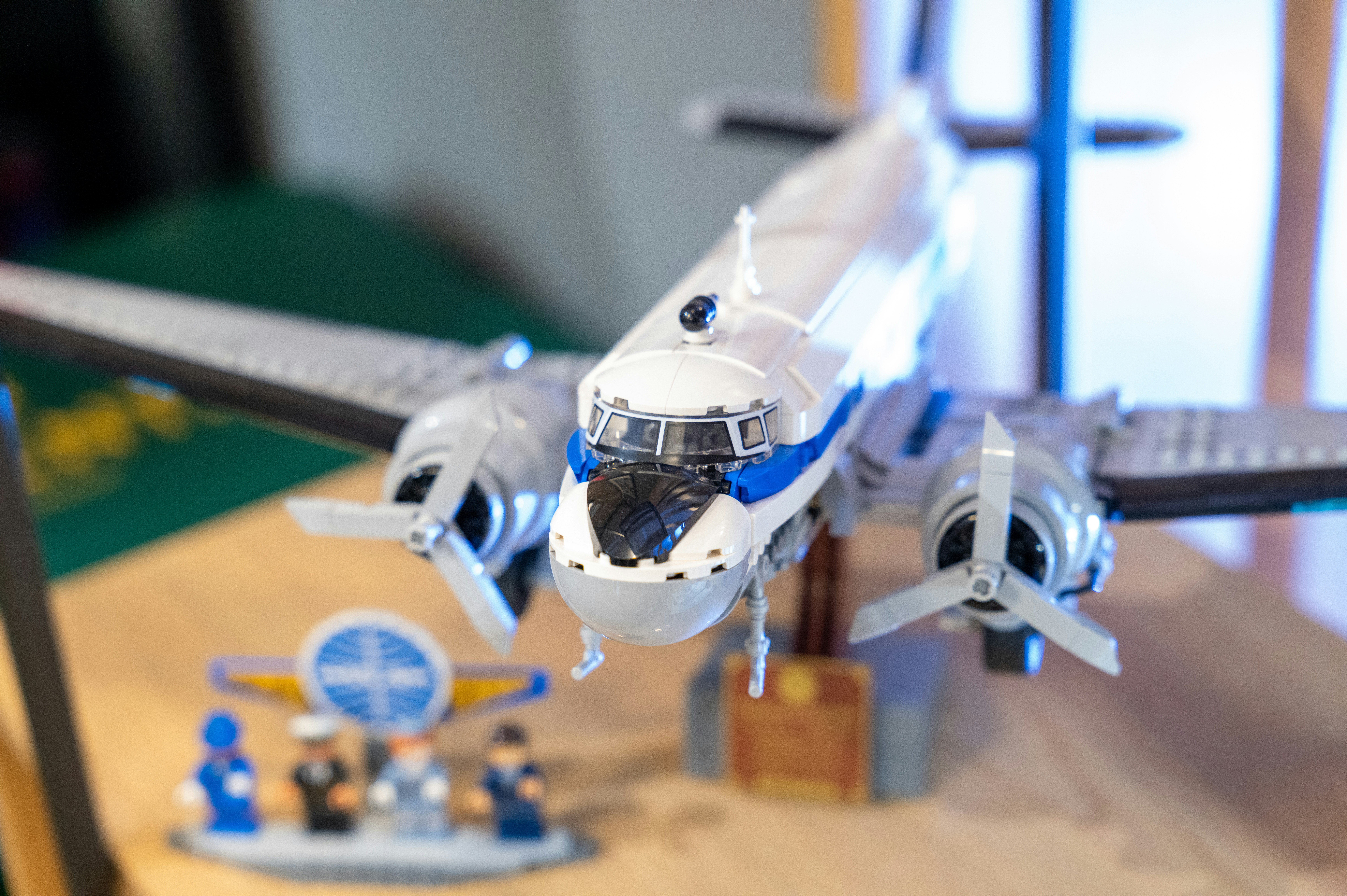 A detailed LEGO passenger airplane model photographed from the front with a shallow depth of field, emphasizing the cockpit and engines while softening the background for a clean, playful composition.