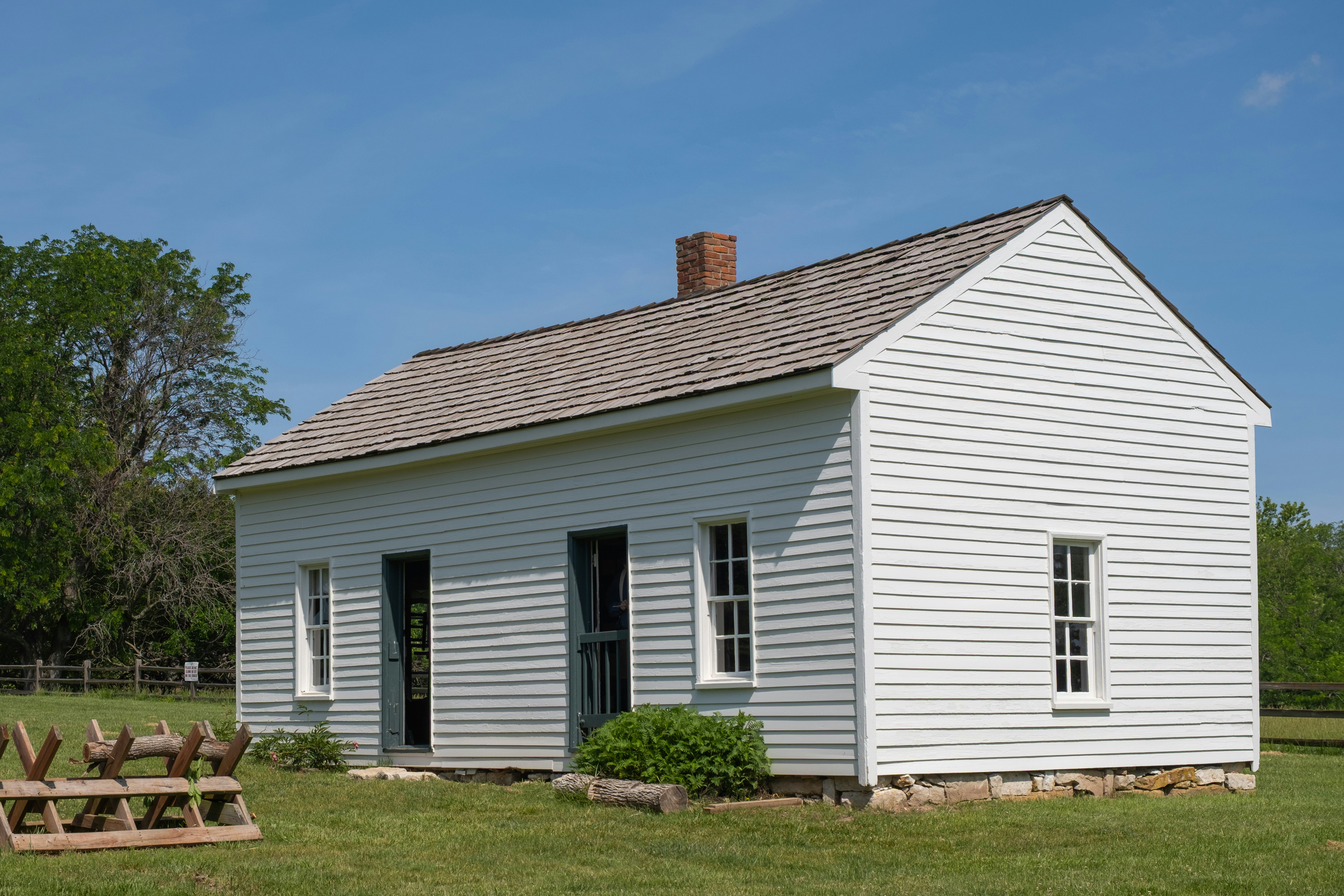 White cottage under a bright sky with a rustic lawn and picnic table