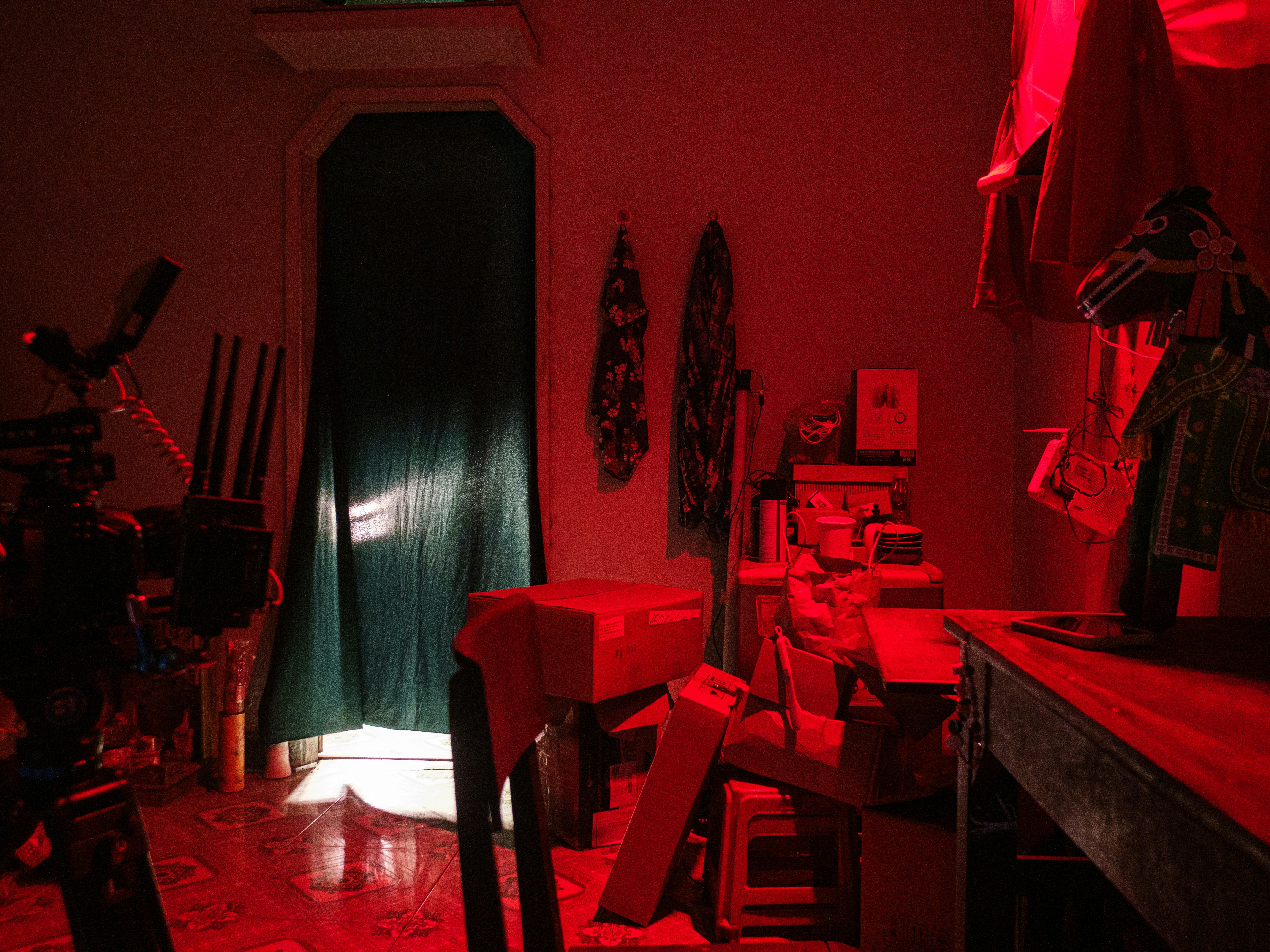 Red-lit Workshop Stacks: Dim Studio Amid Curated Clutter