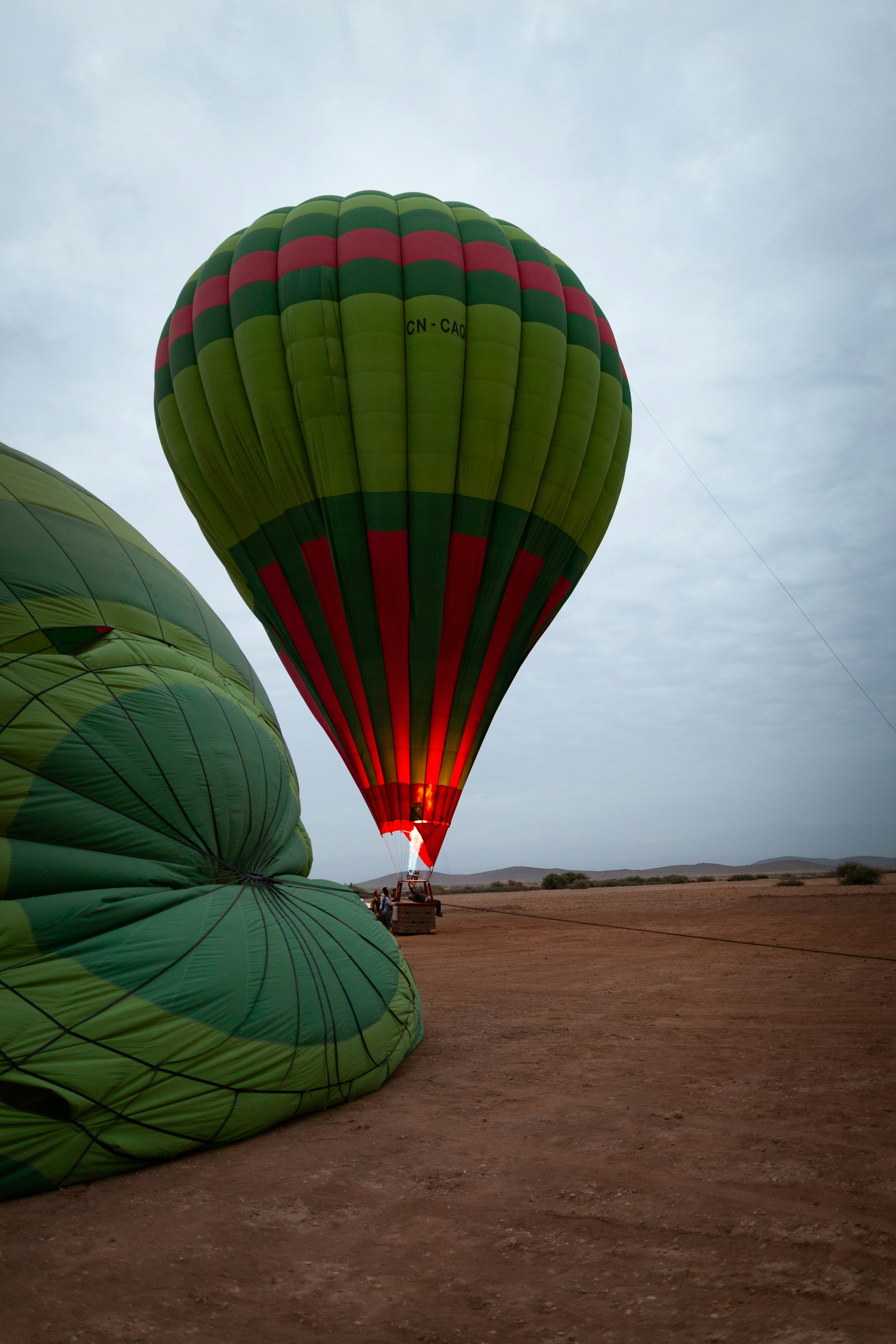 Emergence: A Green-Red Hot-Air Balloon Rises Over Desert Tarmac