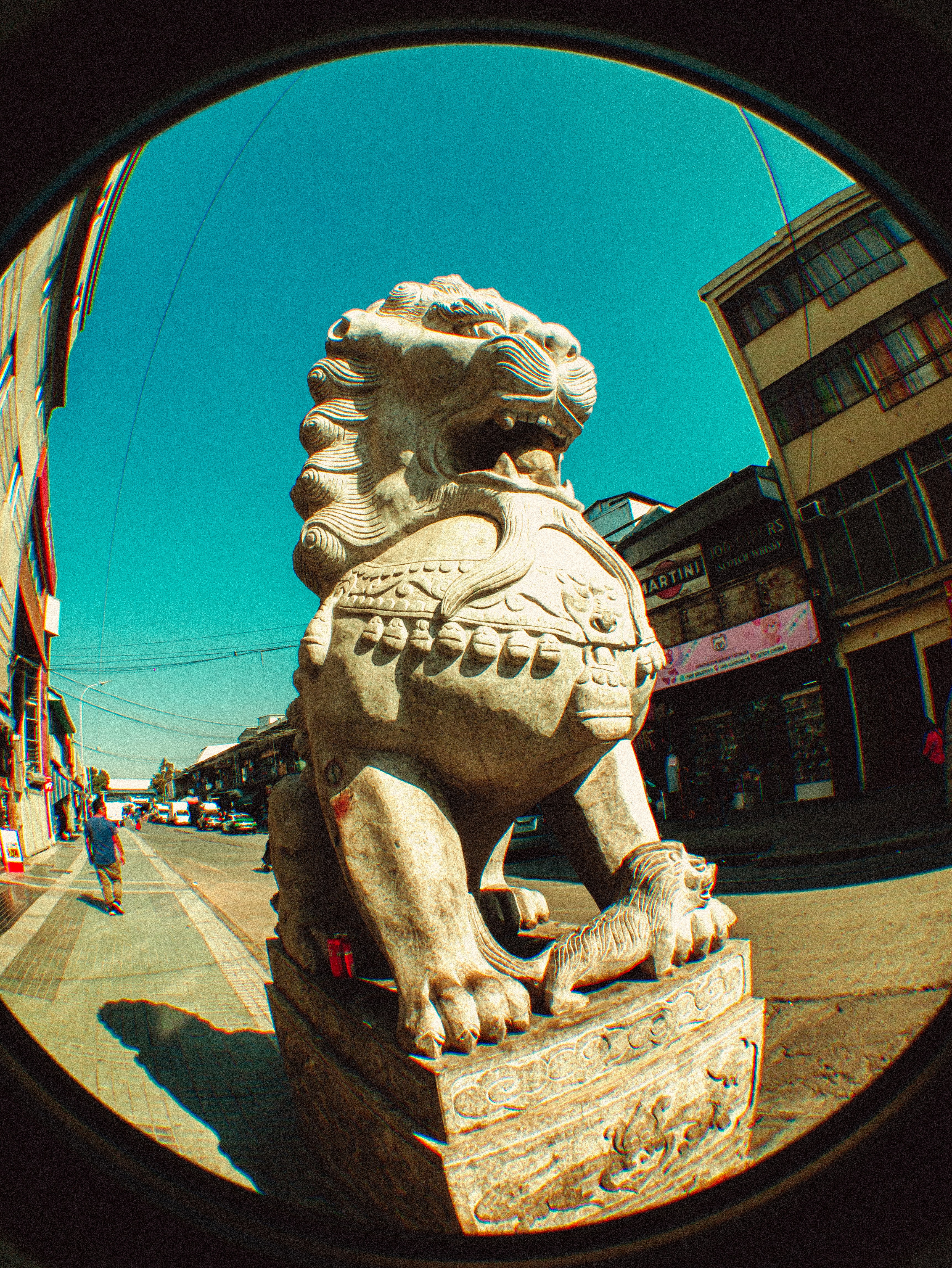 Guardian of the Street: A Dragon Statue Amid a Sunlit Urban Bend