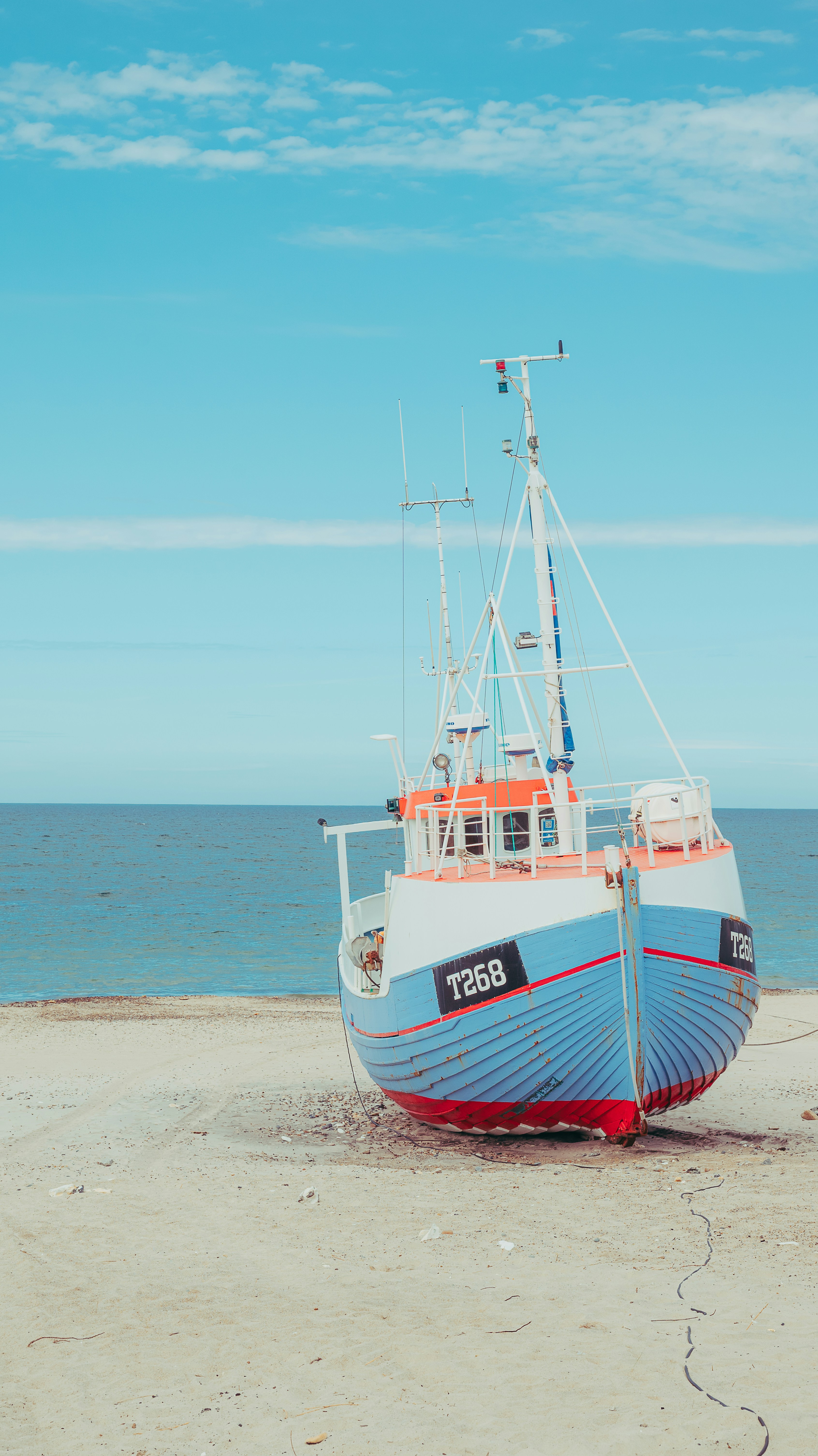 Beached Behemoth: A Blue-and-White Boat Resting on Sunlit Sand
