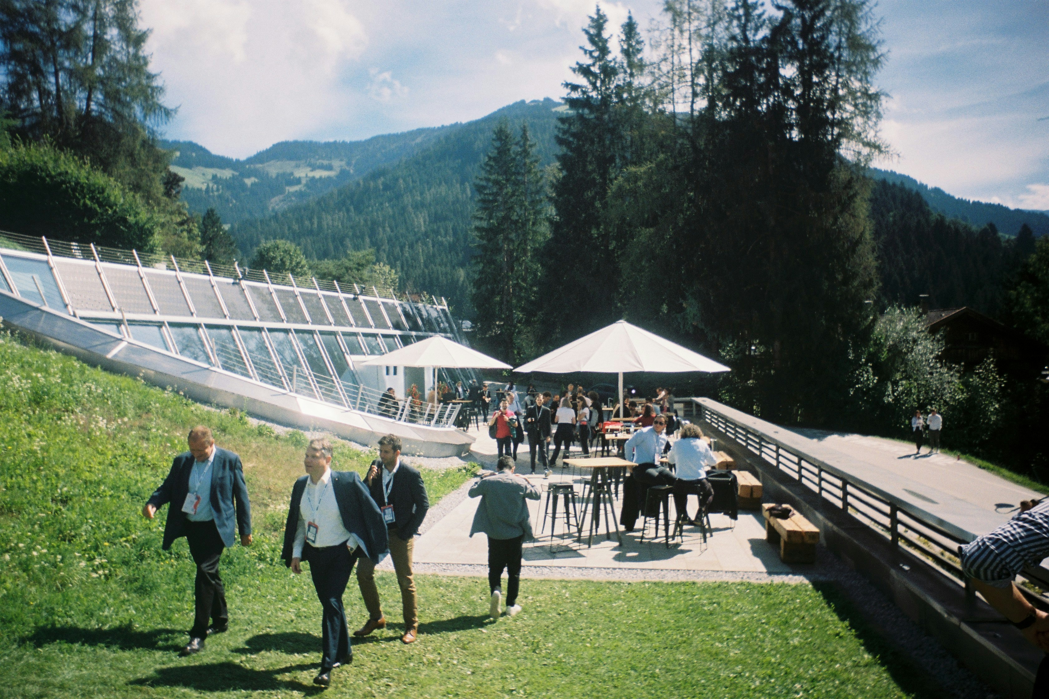 Alpine Terrace Assembly: Guests mingle under umbrellas with mountains in the backdrop