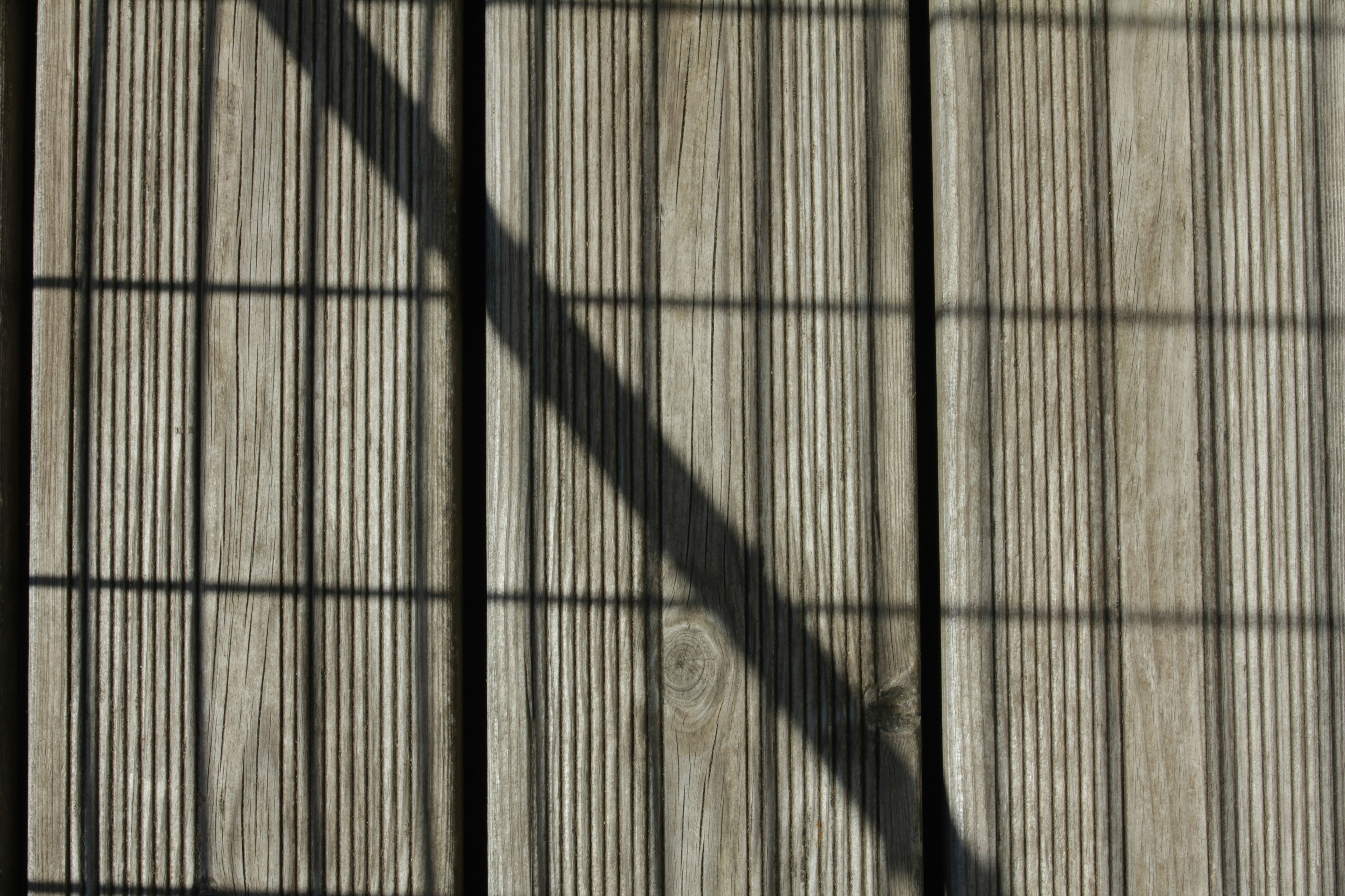 Shadows Over Planks: A Quiet Shadow Crossing the Wood Grain