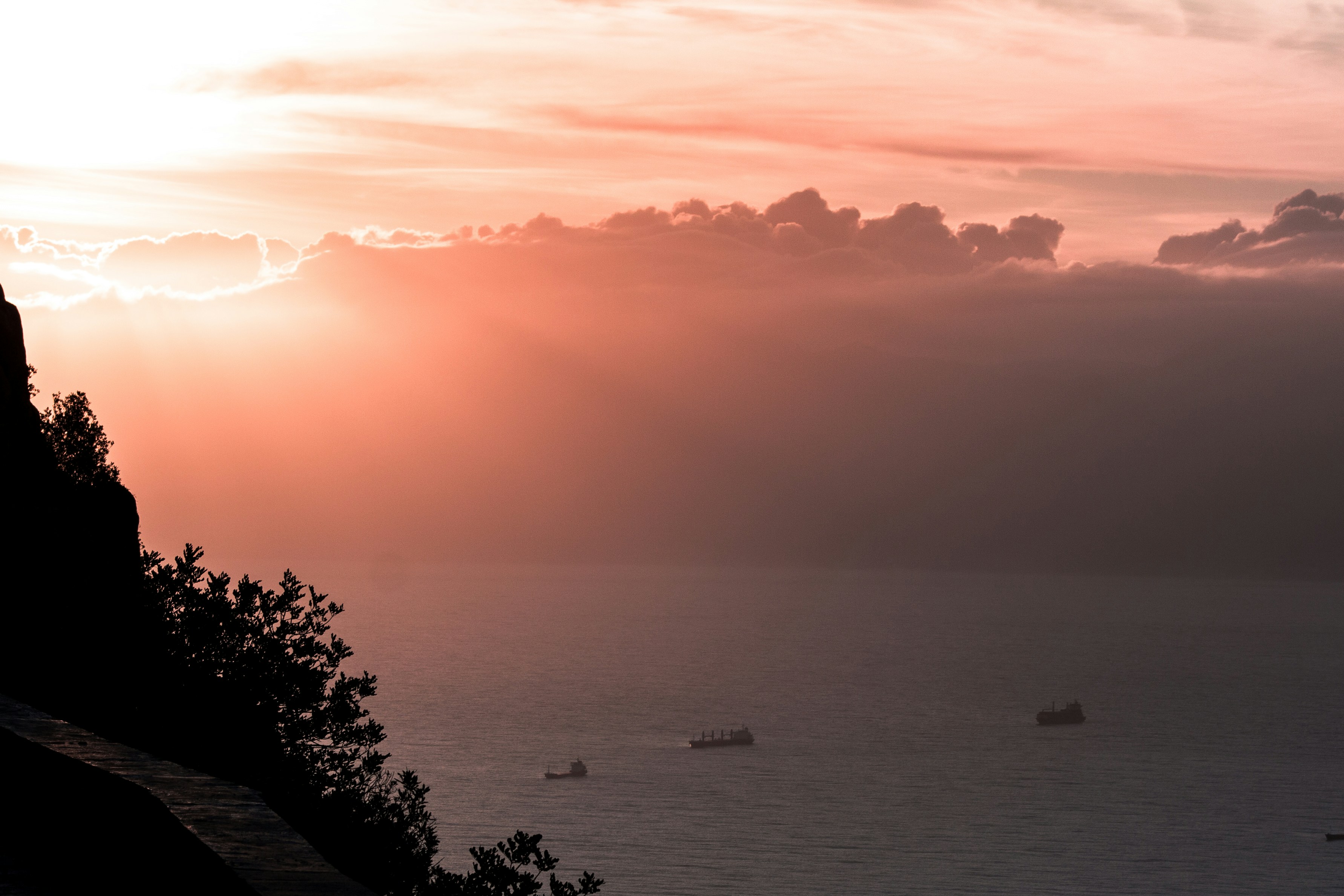 Sunset Over a Quiet Sea: silhouette of a cliff and distant ships