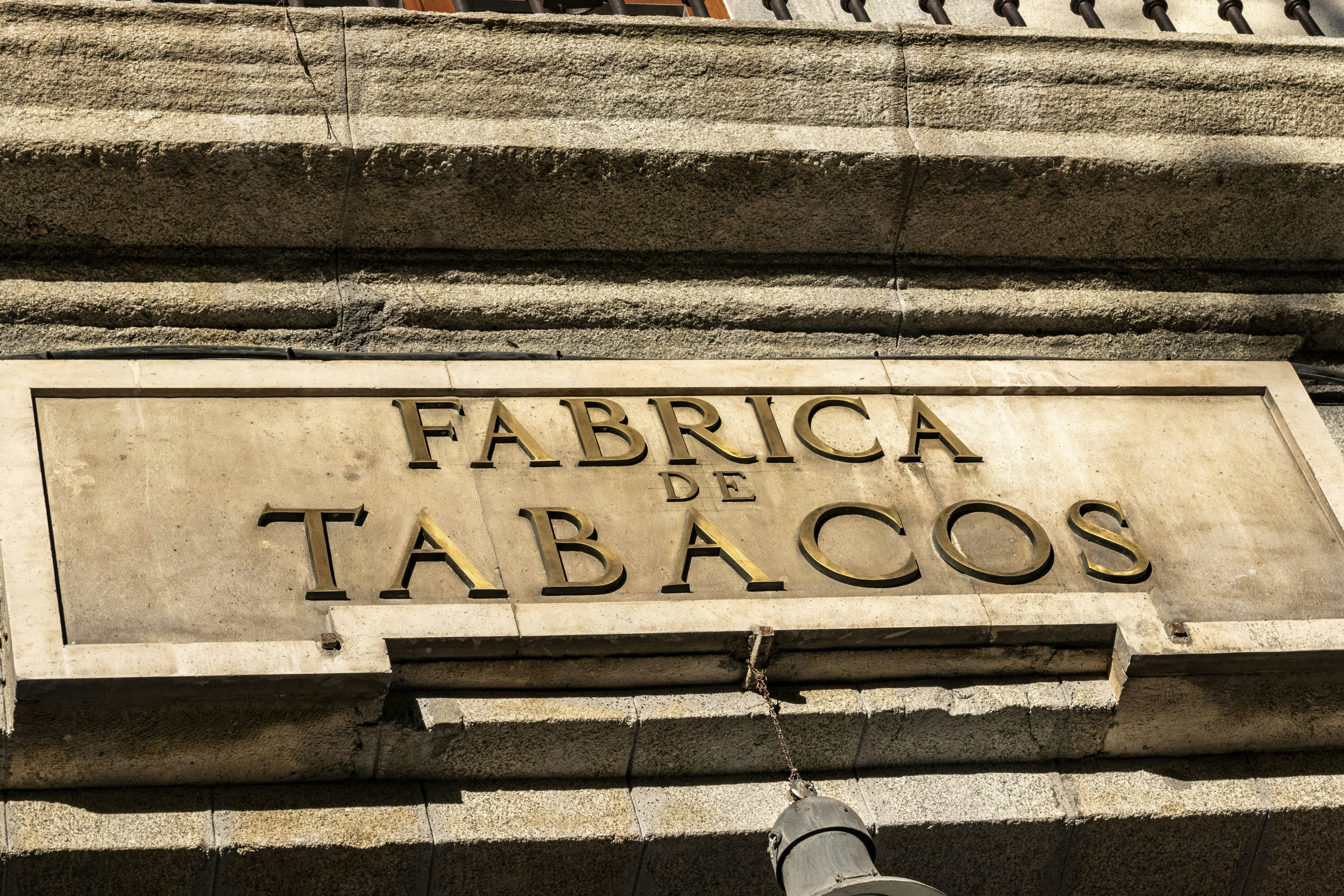 Close-up of a weathered stone sign reading 'FABRICA DE TABACOS' on a historic facade, conveying aged architectural texture and craftsmanship.