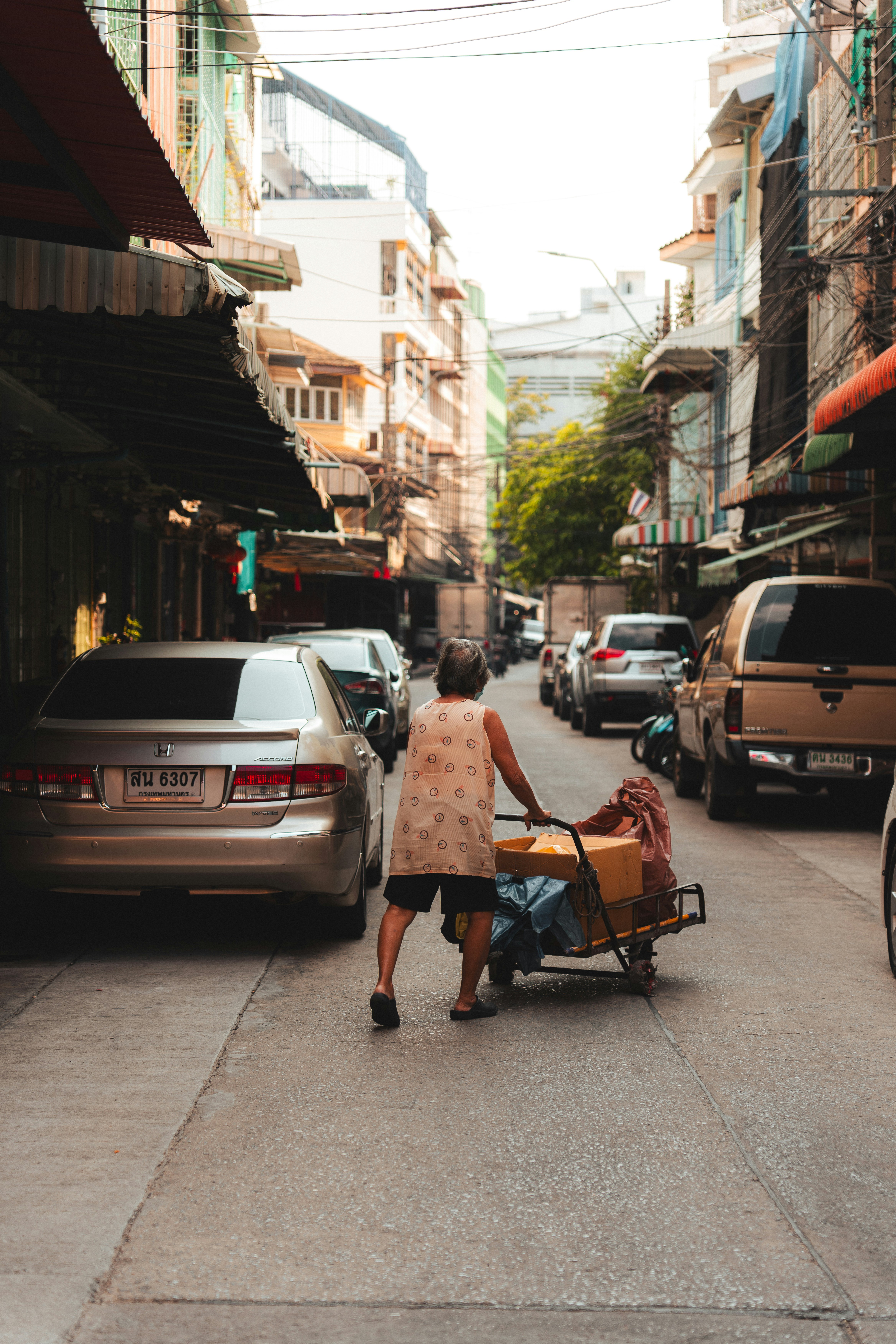 Street Cart and Elderly Worker Pushing a Load Along a Narrow Alley