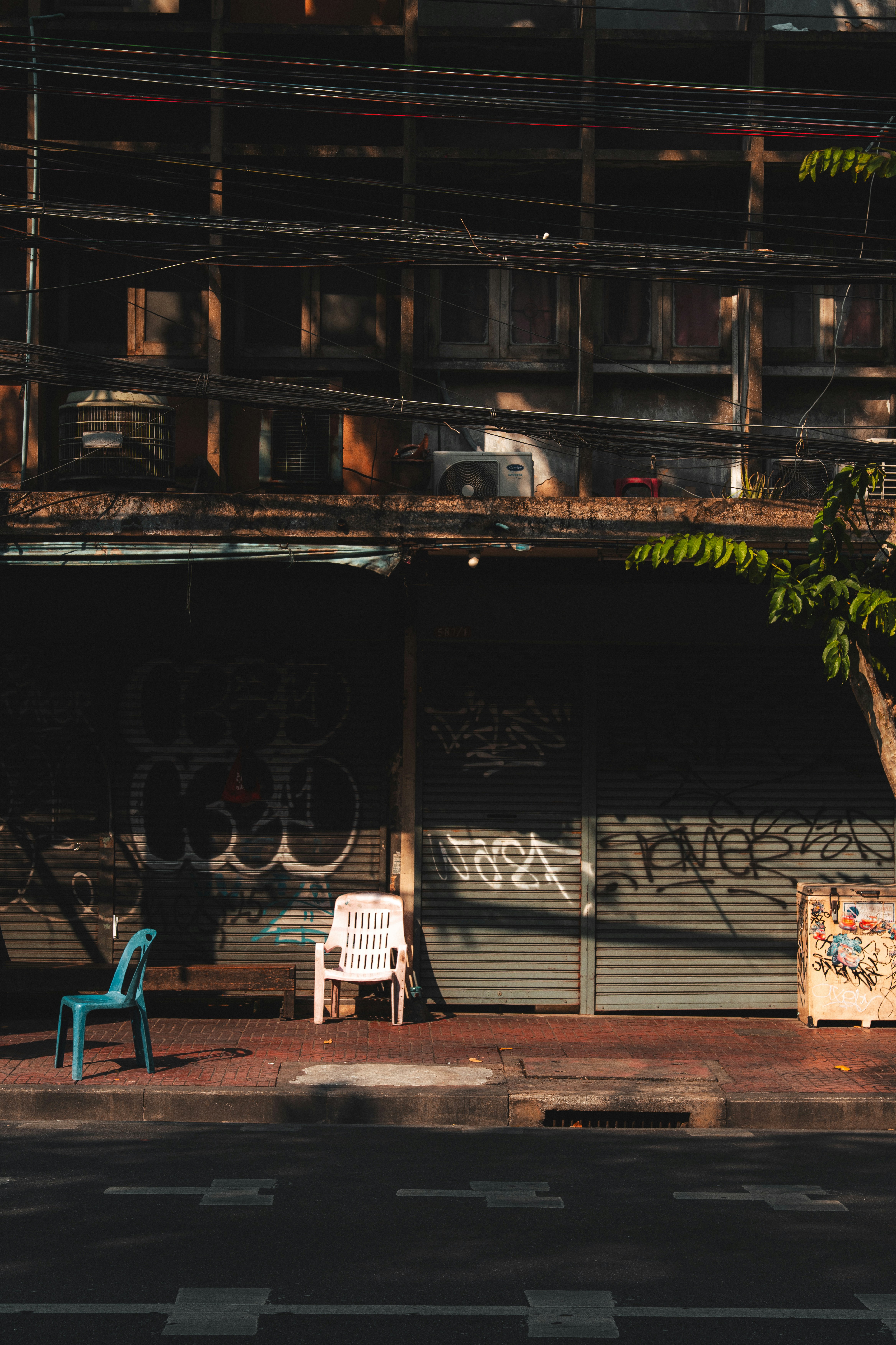 Abandoned storefronts and street seating under graffiti shadows