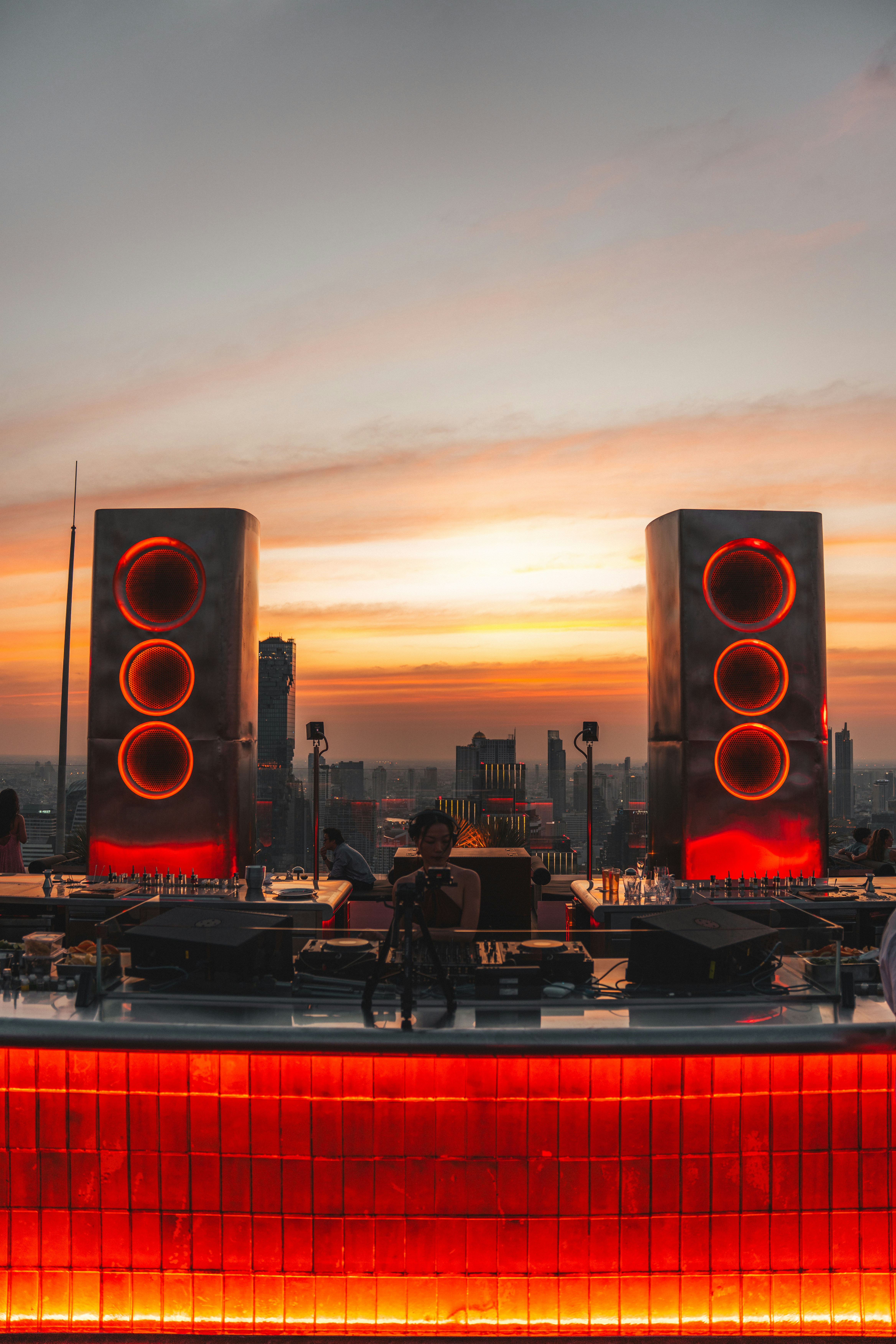 Neon-Illuminated Rooftop DJ Booth Over a Dusk Skyline