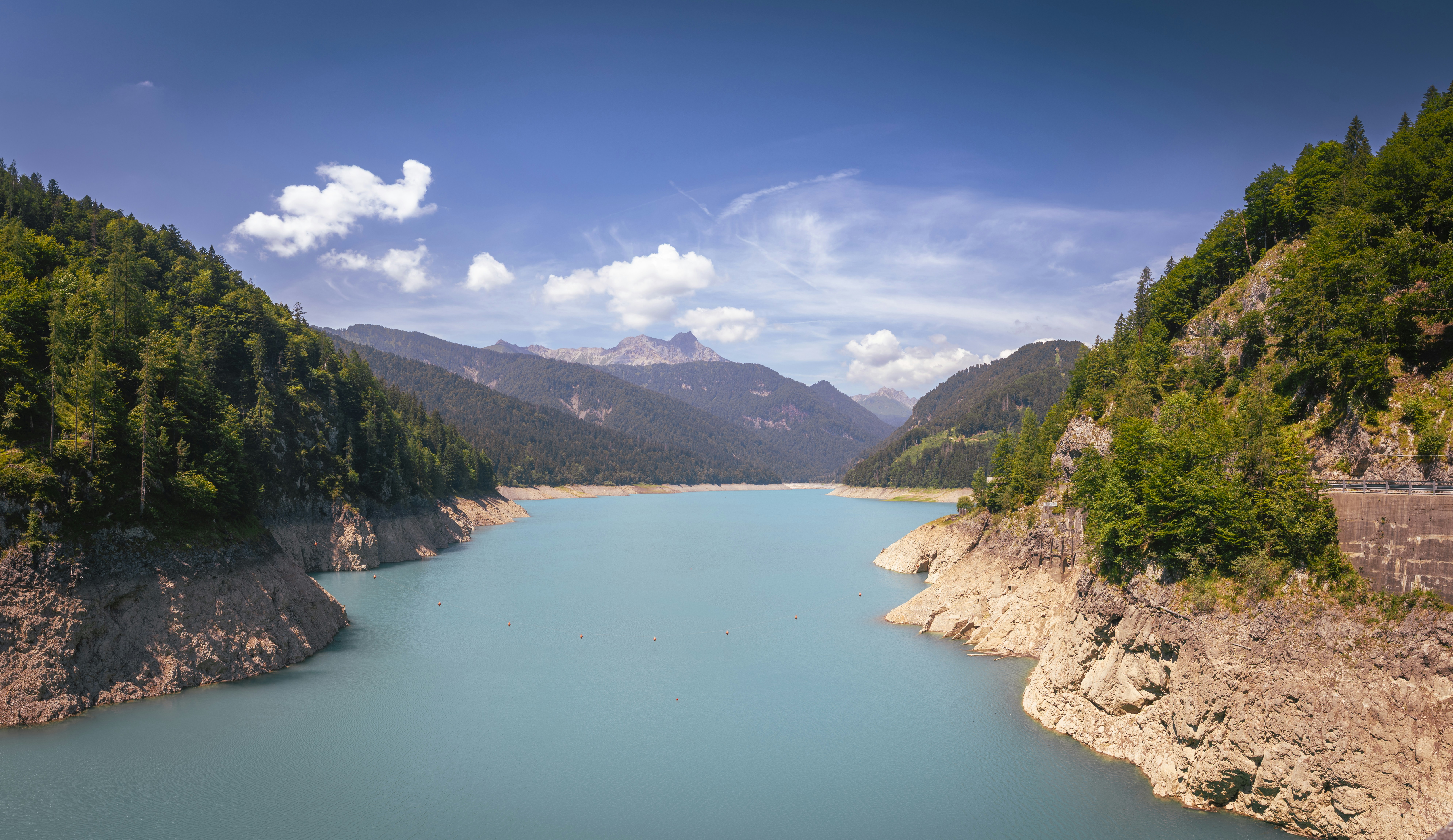 Turquoise Reservoir Between Forested Ridges Under a Cerulean Sky