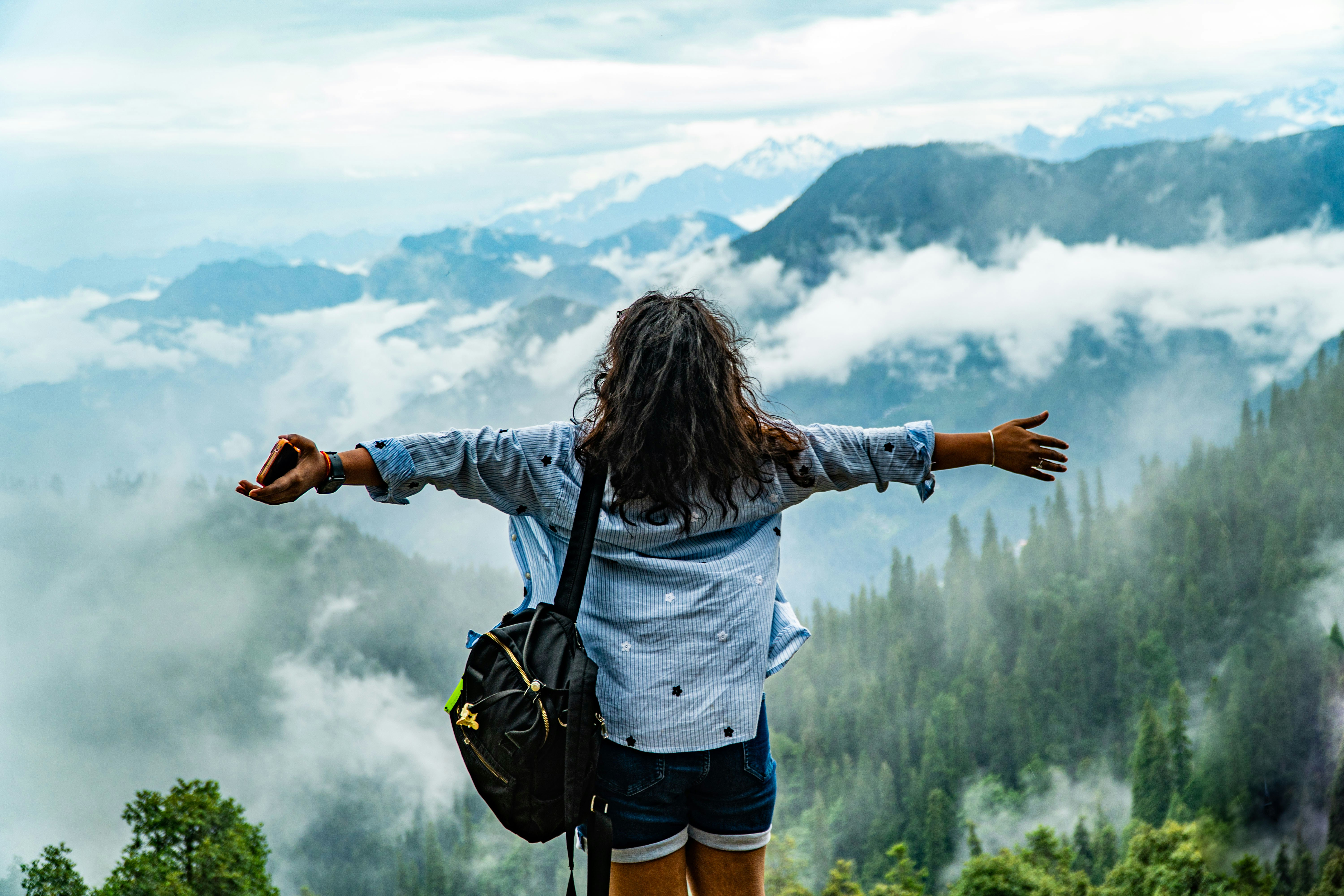 Toward the Edge: A Hiker Embracing the Mist on a Mountain Vista