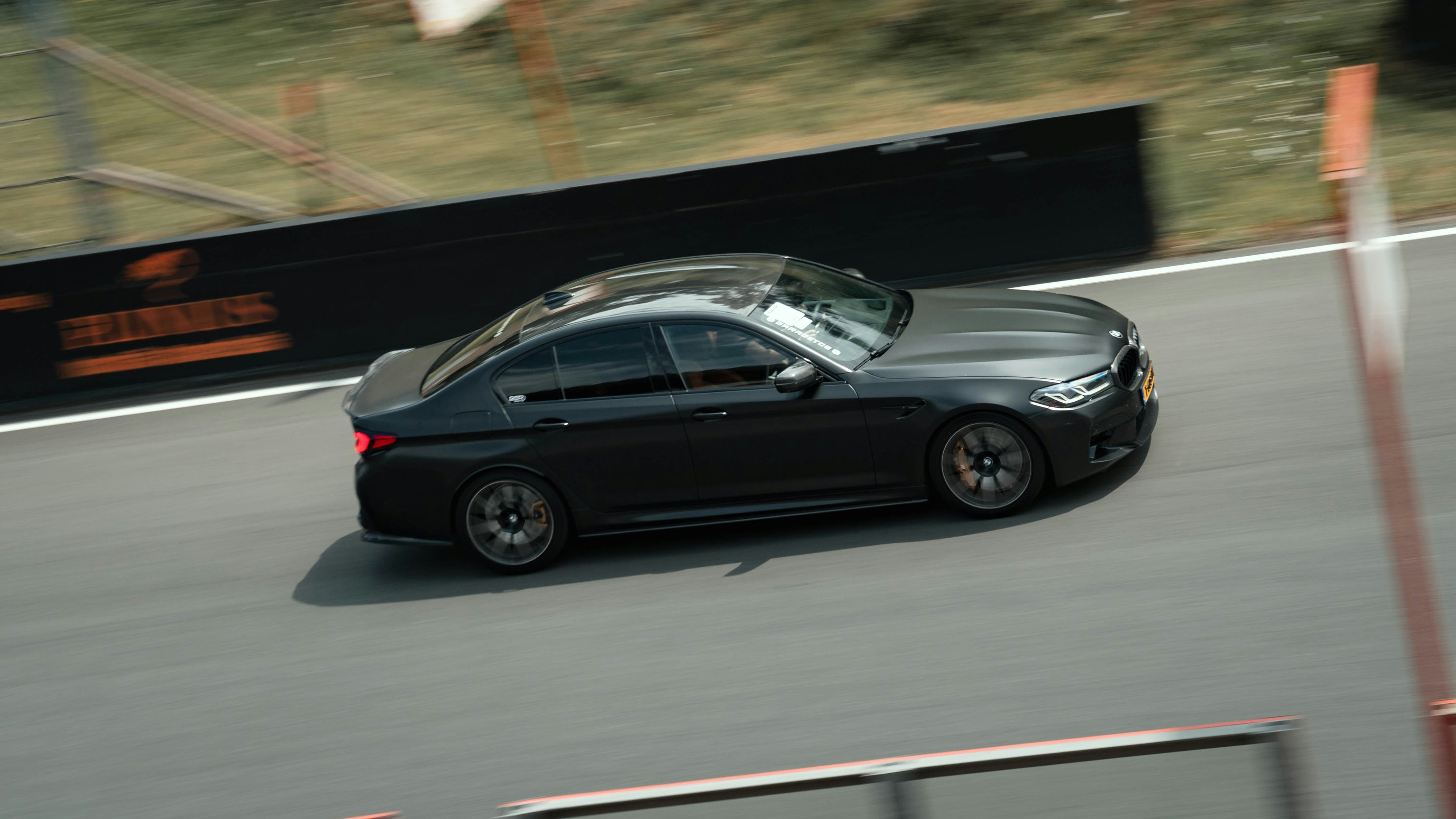 Black sports sedan in mid‑turn on sunlit track