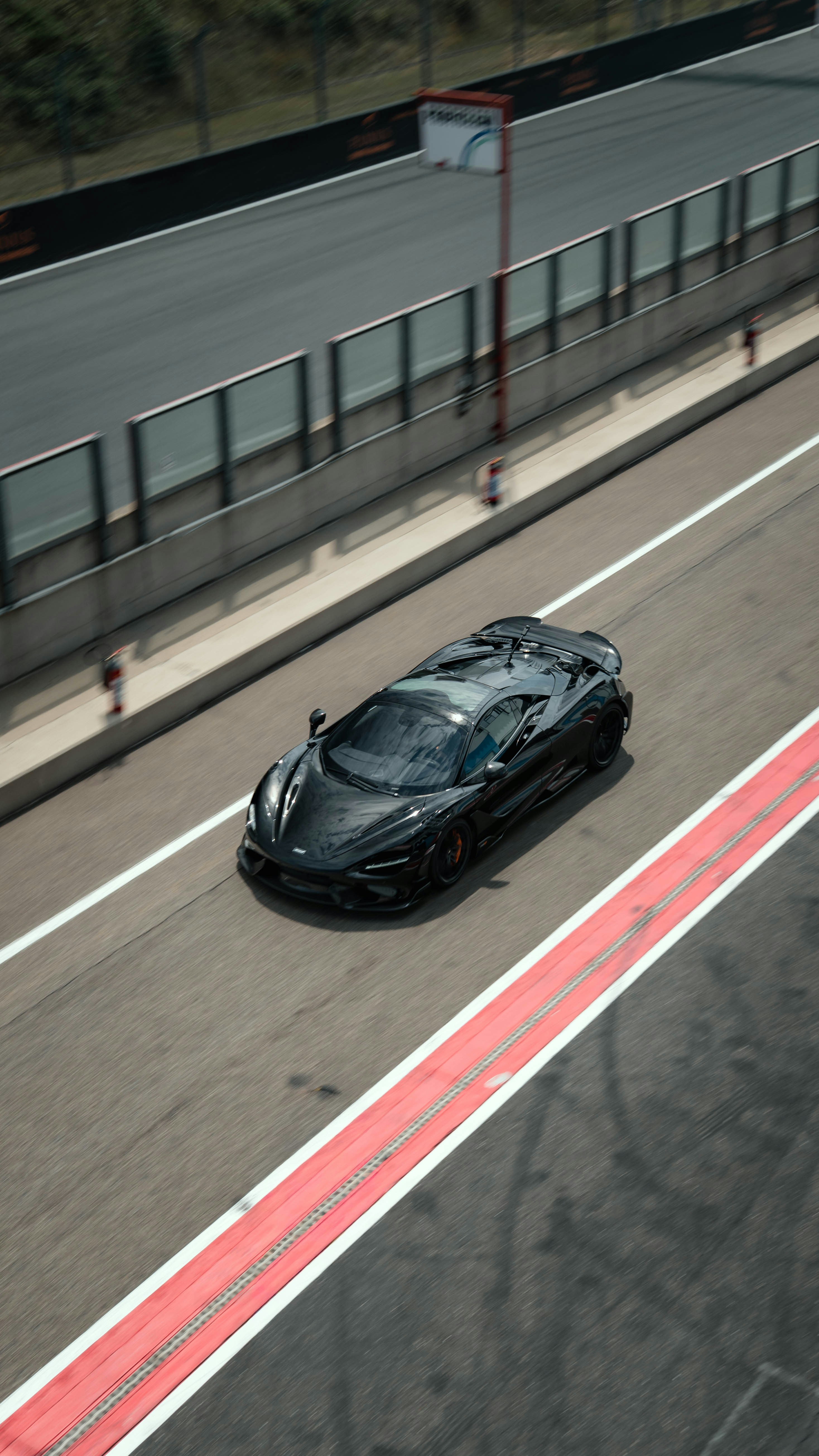Mid-Race Glide: Black Hypercar Streaming Along the Pit Lane