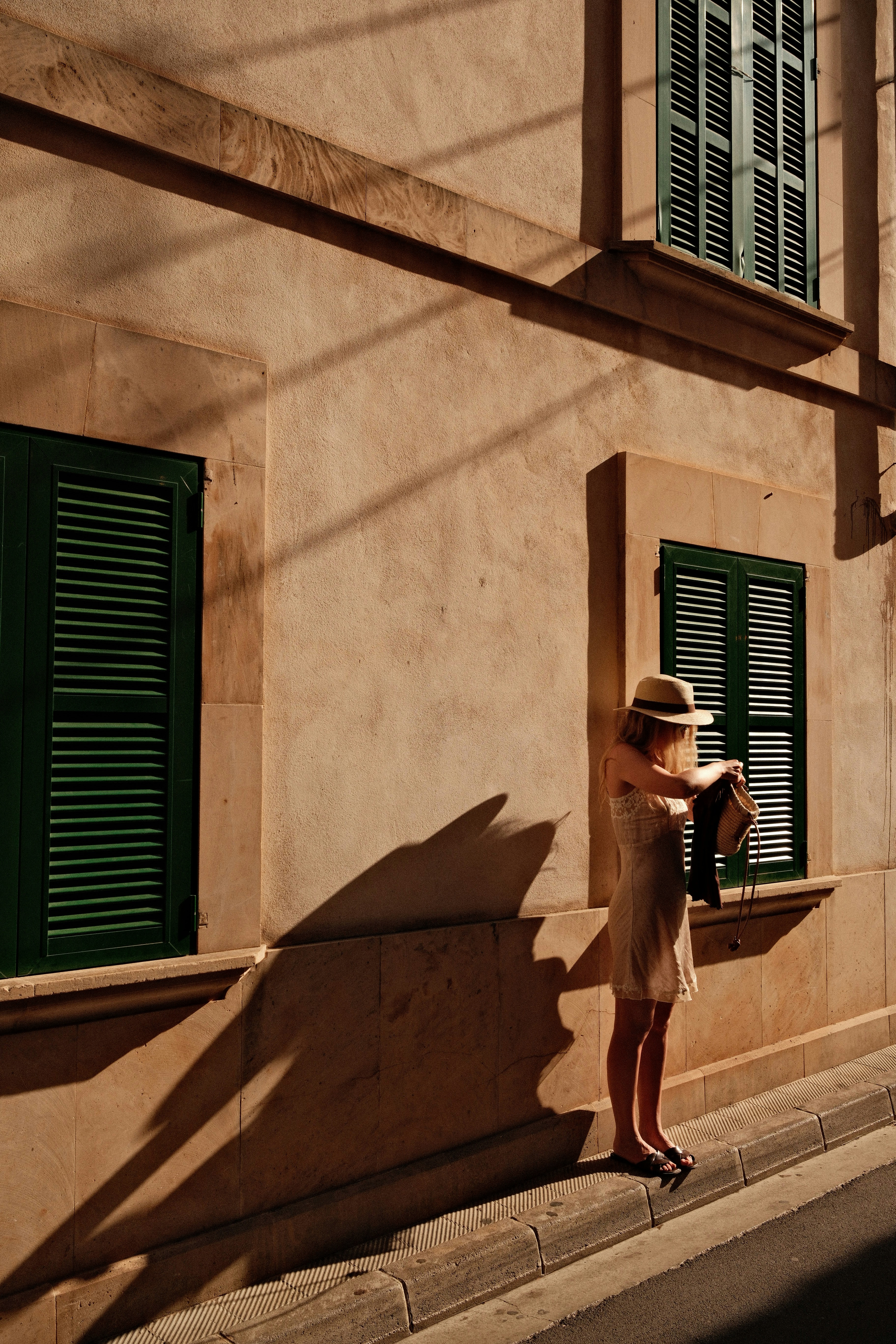 Sunlit Street Portrait: Hat, Handbag, and Shadow Play