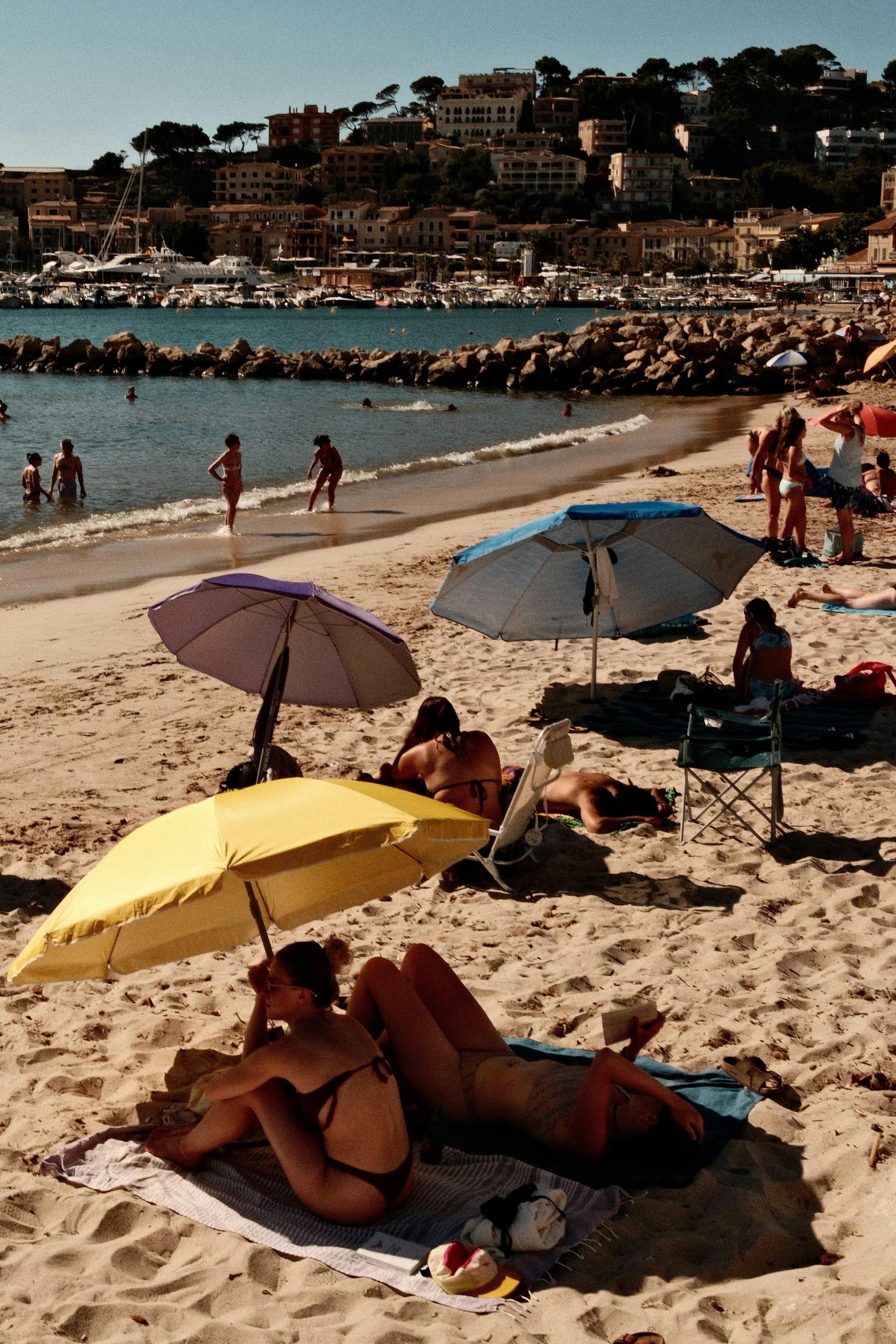 Sunlit Beach Frenzy: Umbrellas, Sand, and Sea Beyond a Bustling Shore