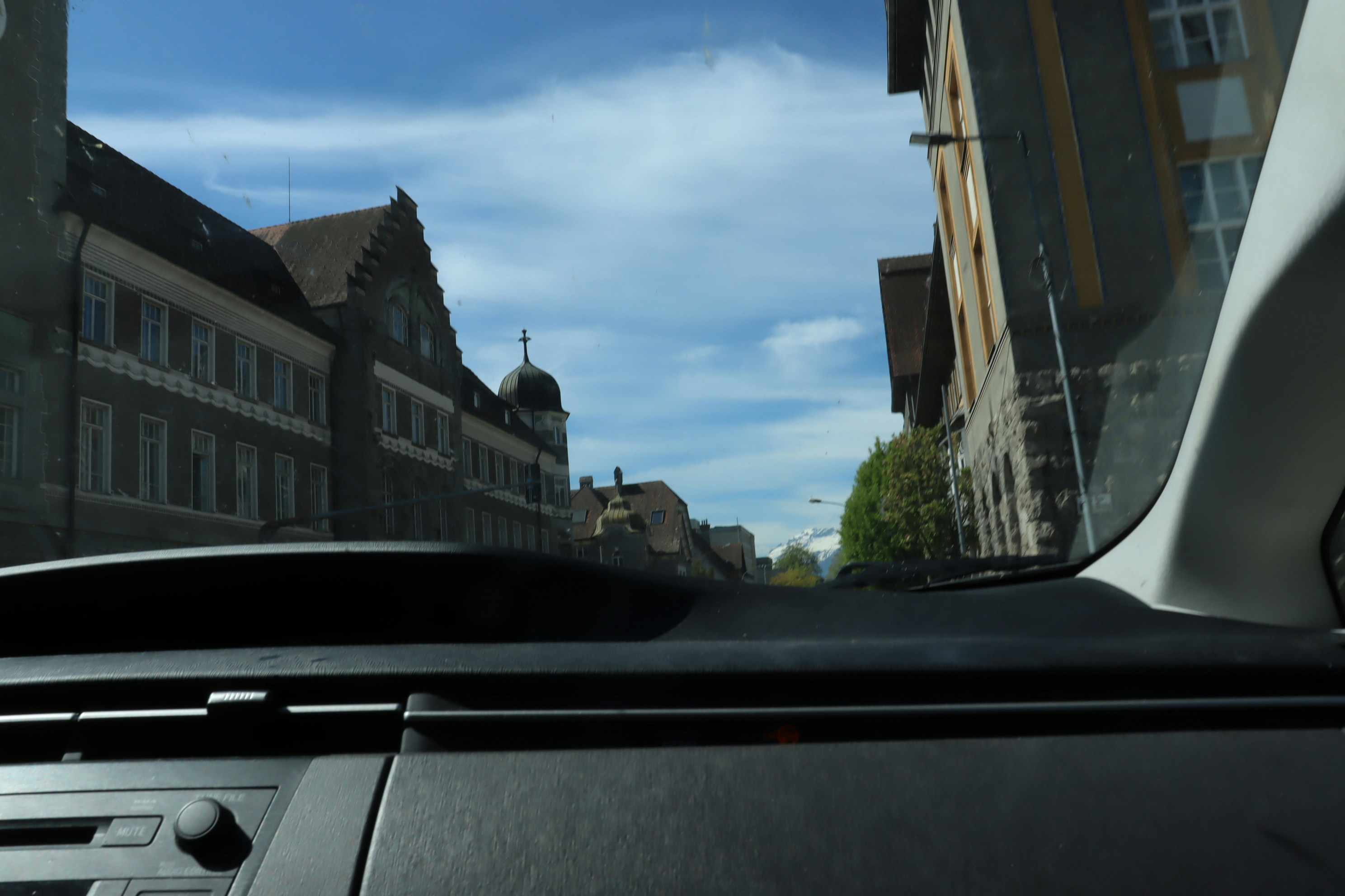 Street View Through a Car Windshield: Narrow European Avenue Framed by Buildings