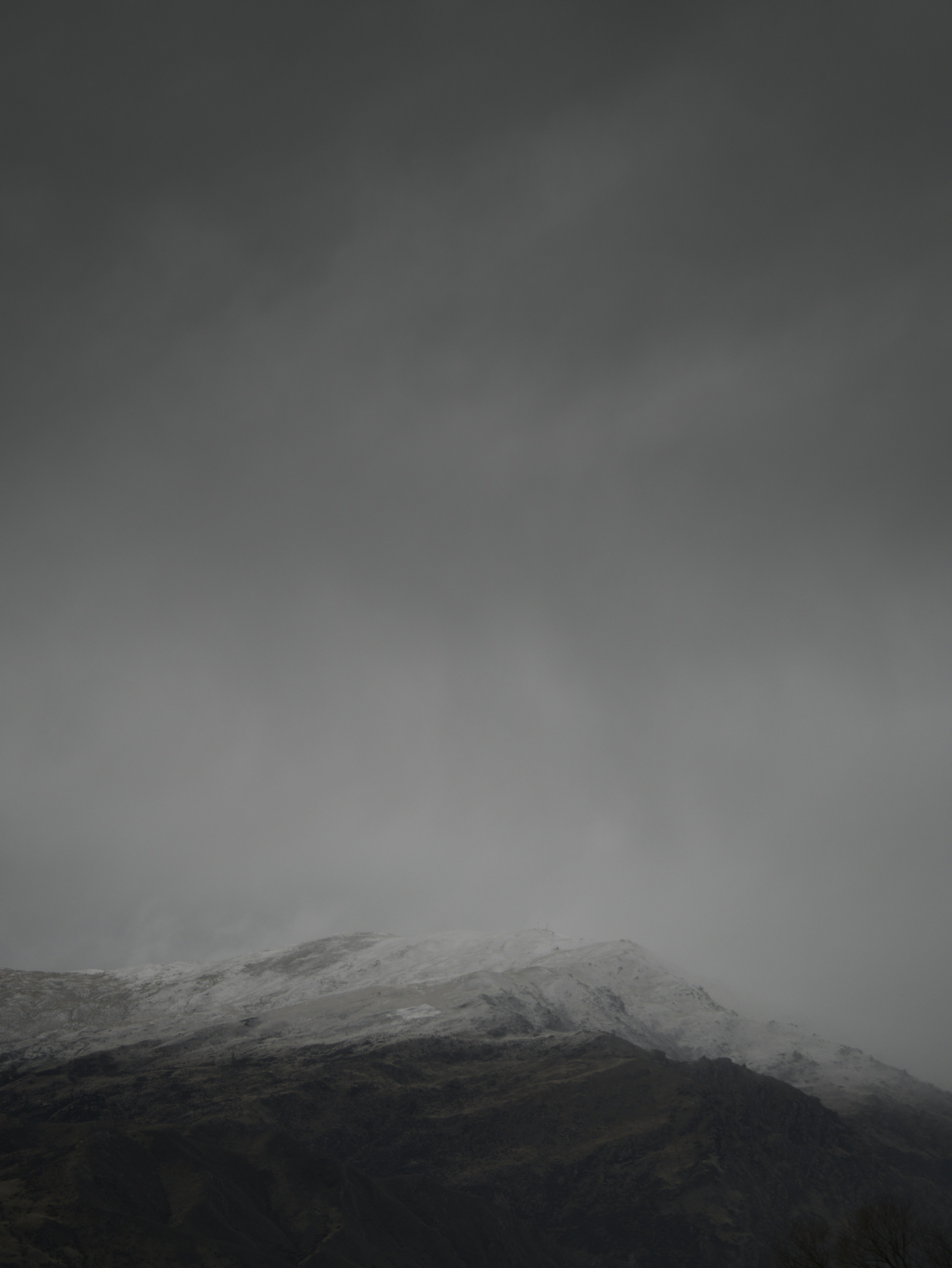 Storm-Wedged Spine: Snow-Capped Ridge Emerging Through Clouds