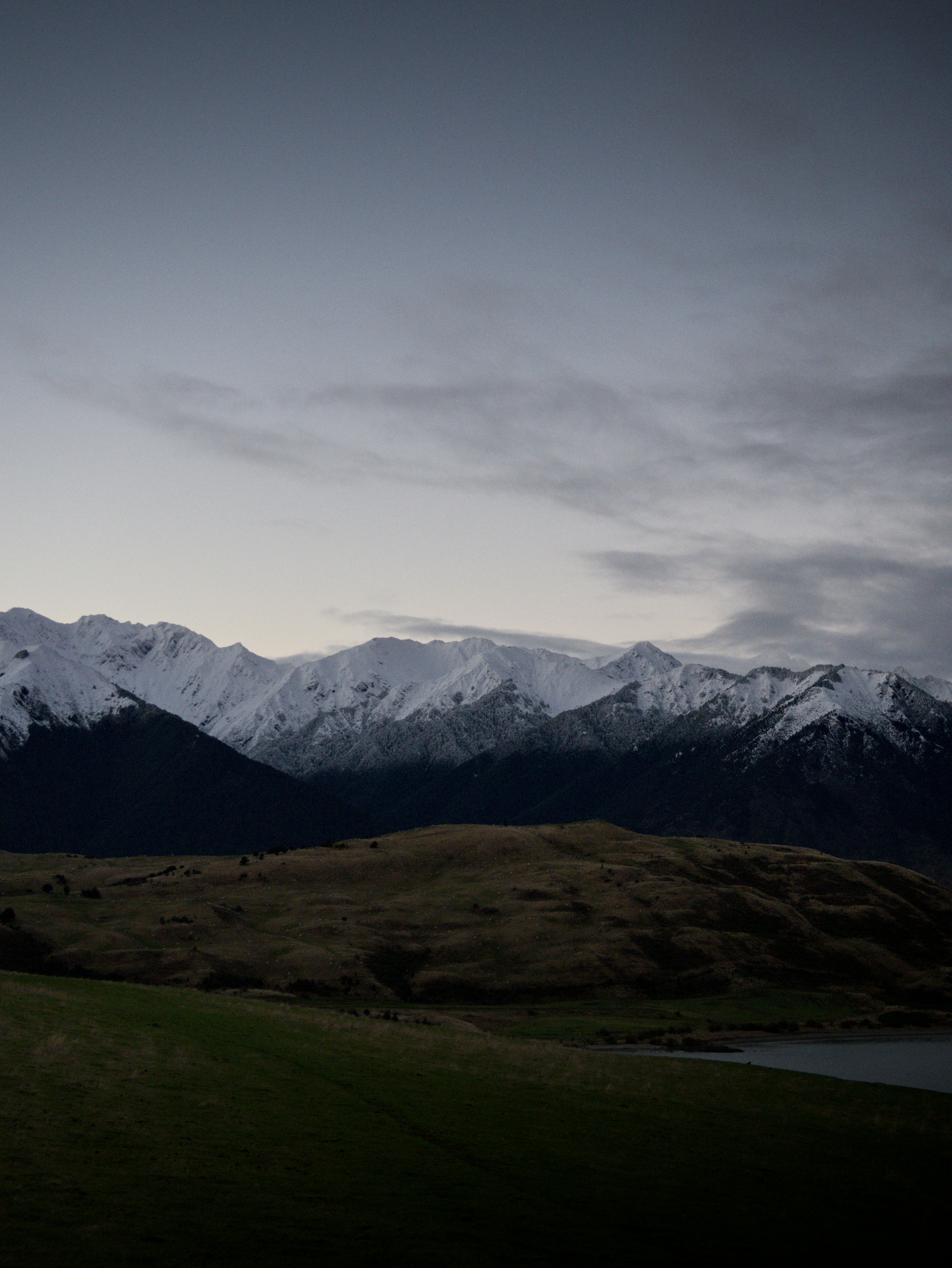 Snow-kissed ridges at twilight over rolling foothills